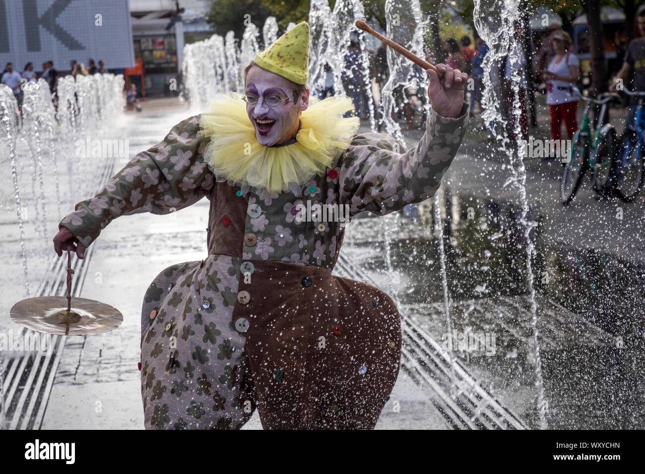 A clown dancing under jets of a pedestrian fountain in the Muzeon Park ...