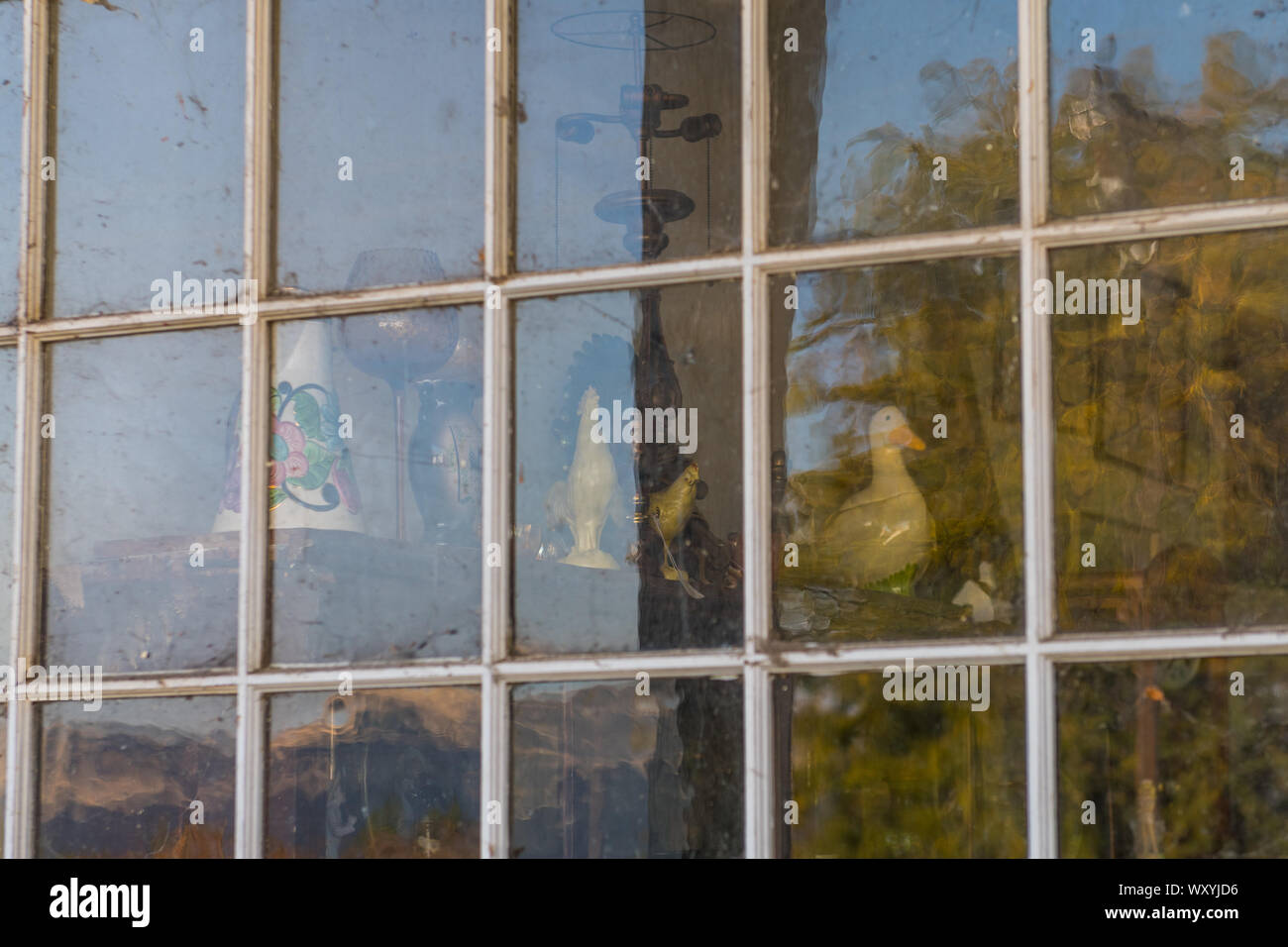 Old decorative objects behind the window of an abandoned gas station in ...