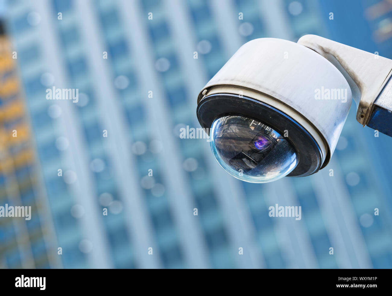 cctv security camera in a city with blury business building on ...