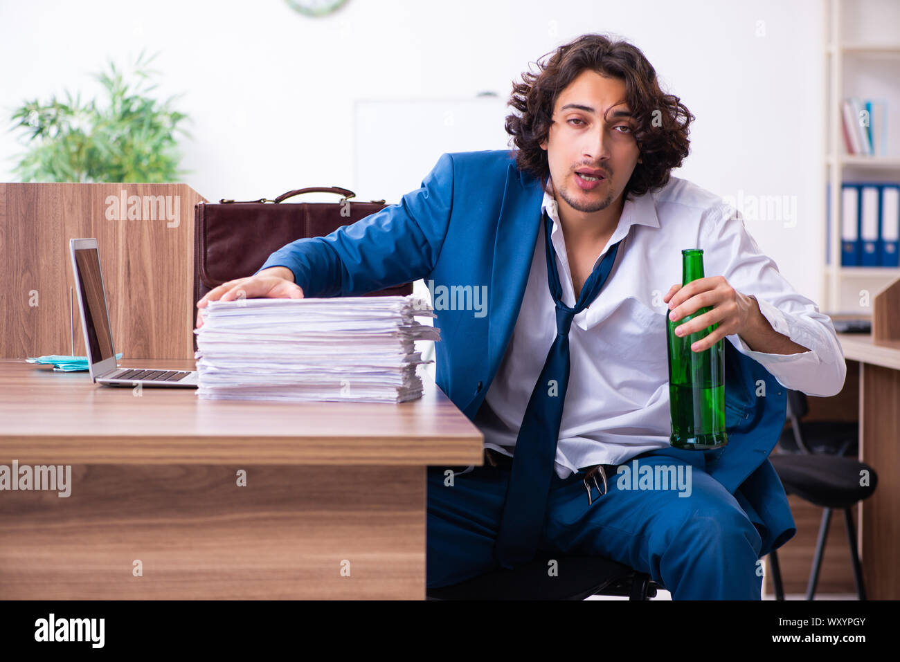 The young drunk employee in the office Stock Photo - Alamy