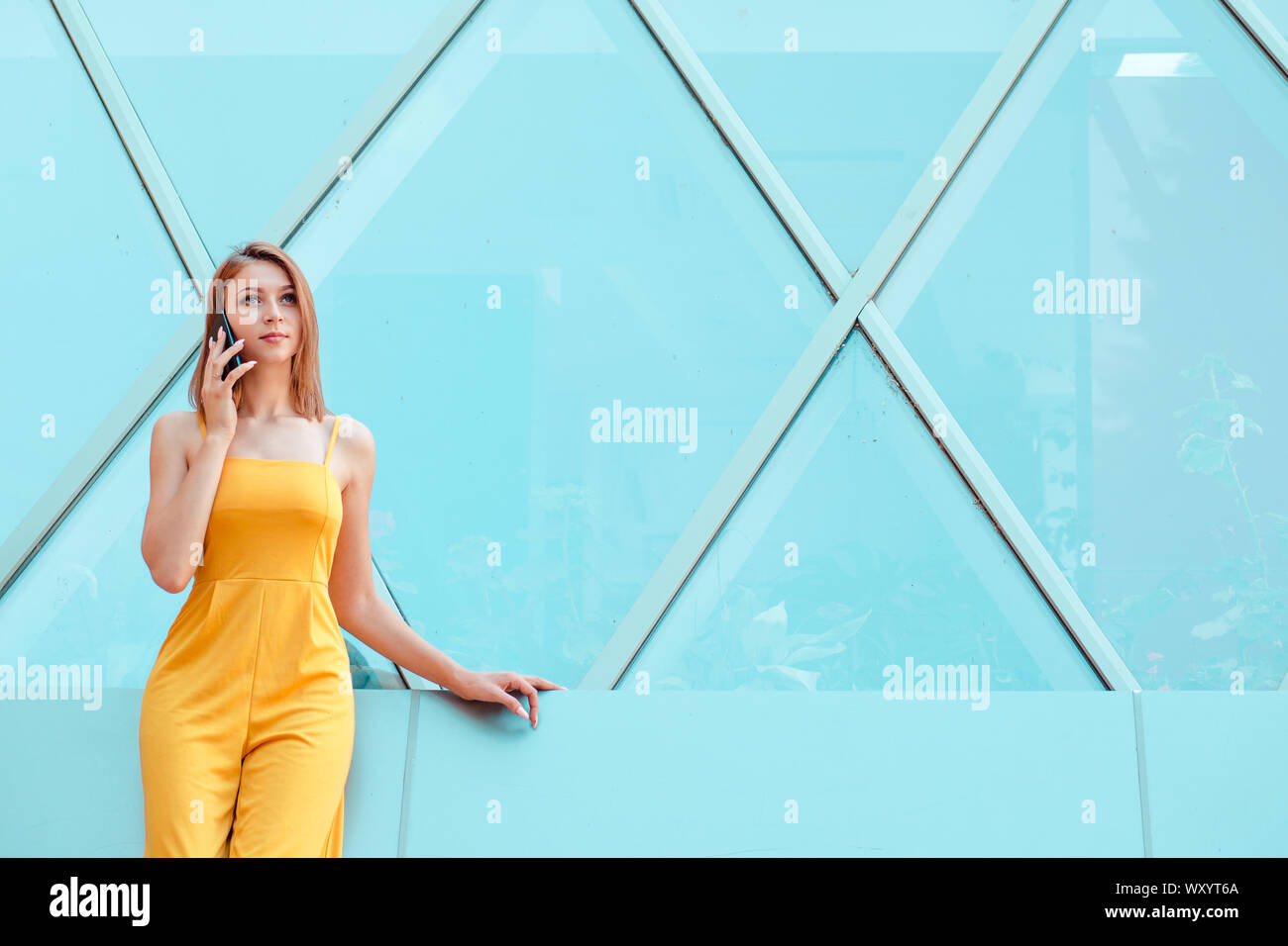 Beautiful woman talking by phone smiling, standing on an urban modern ...