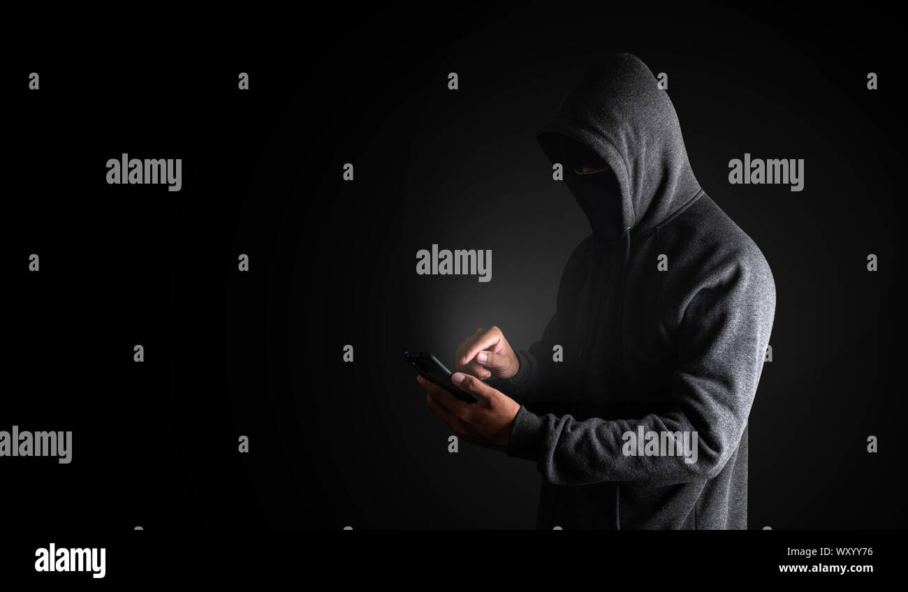 Hacker Using Smartphone. Men in black clothes with hidden face looks at ...