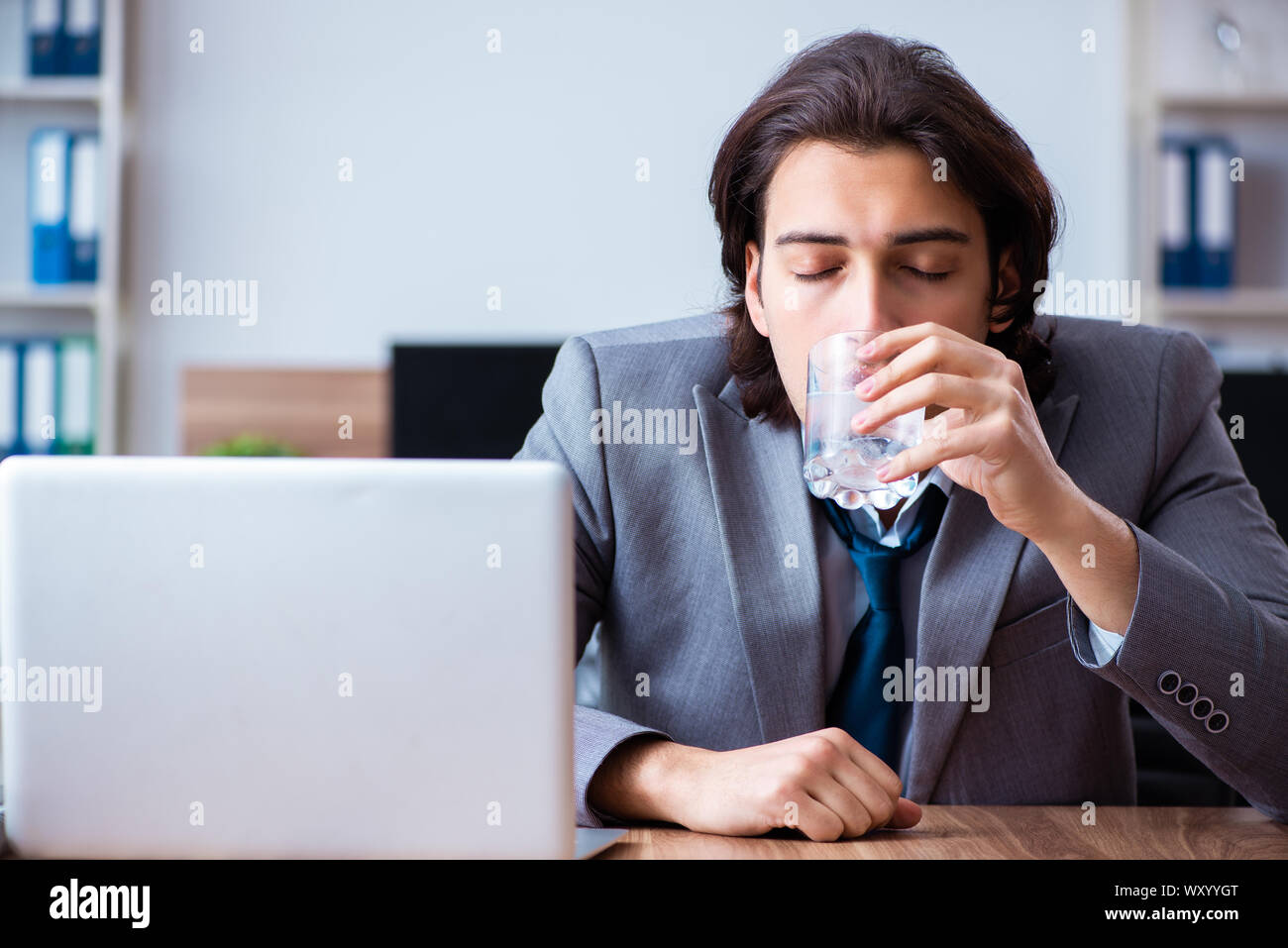 The sick male employee suffering in the office Stock Photo - Alamy