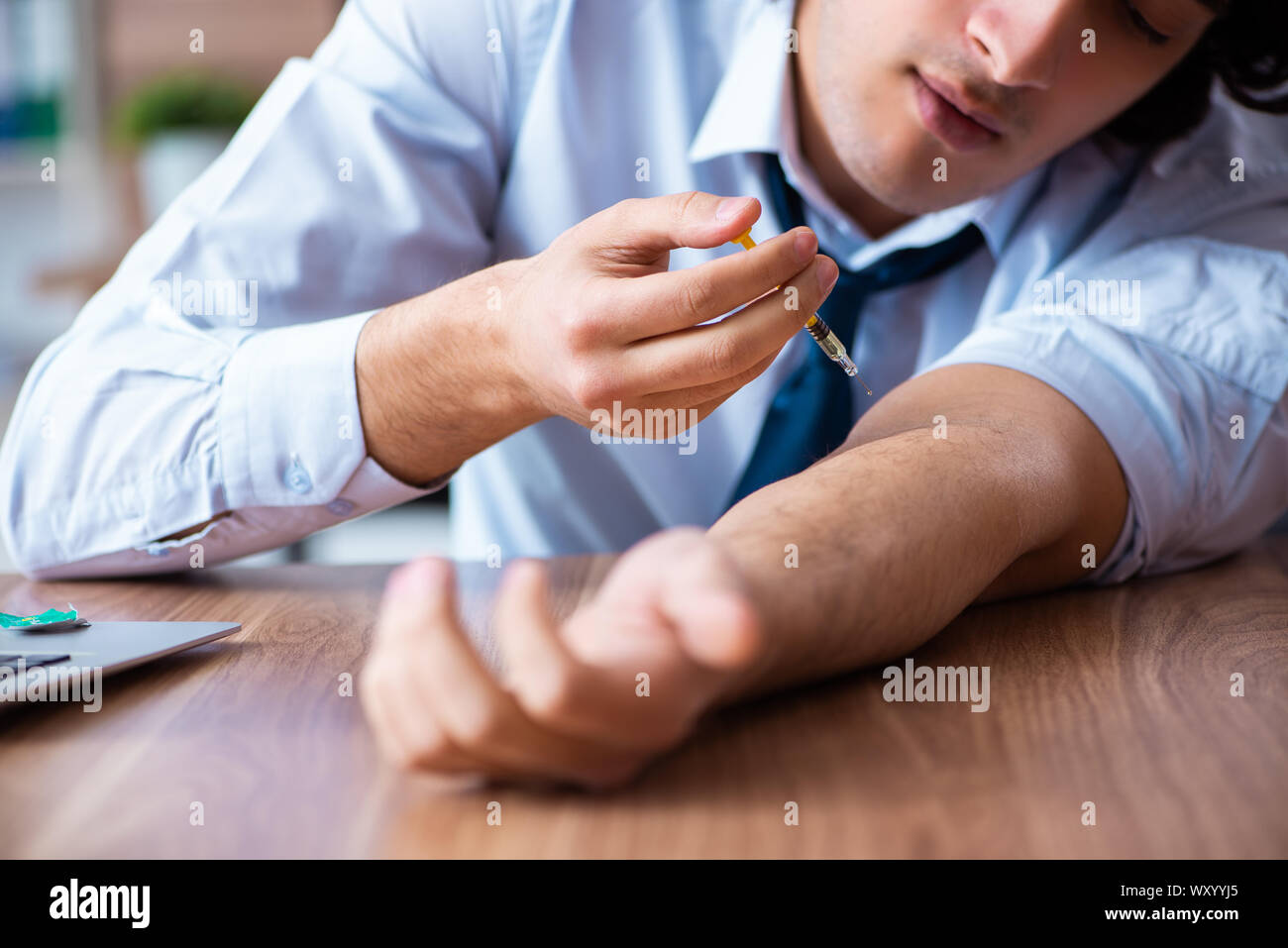 The young man having problems with narcotics at workplace Stock Photo ...