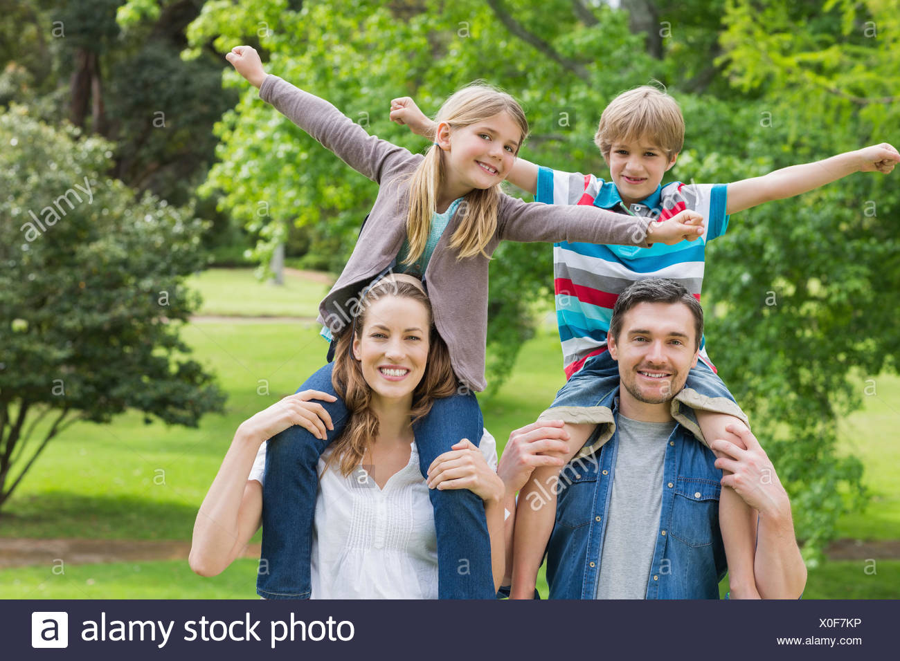 Parents Carrying Children On Shoulders Fun Outdoors High Resolution ...