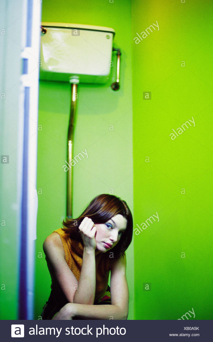 Young Woman Sitting On Toilet High Resolution Stock