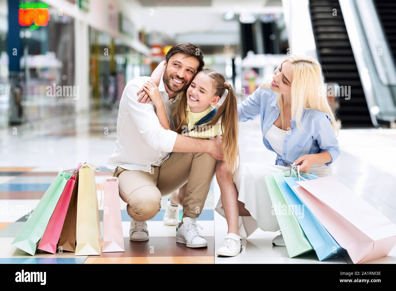 Eltern und Tochter sitzen auf Vouten und Umarmen In der Mall ...