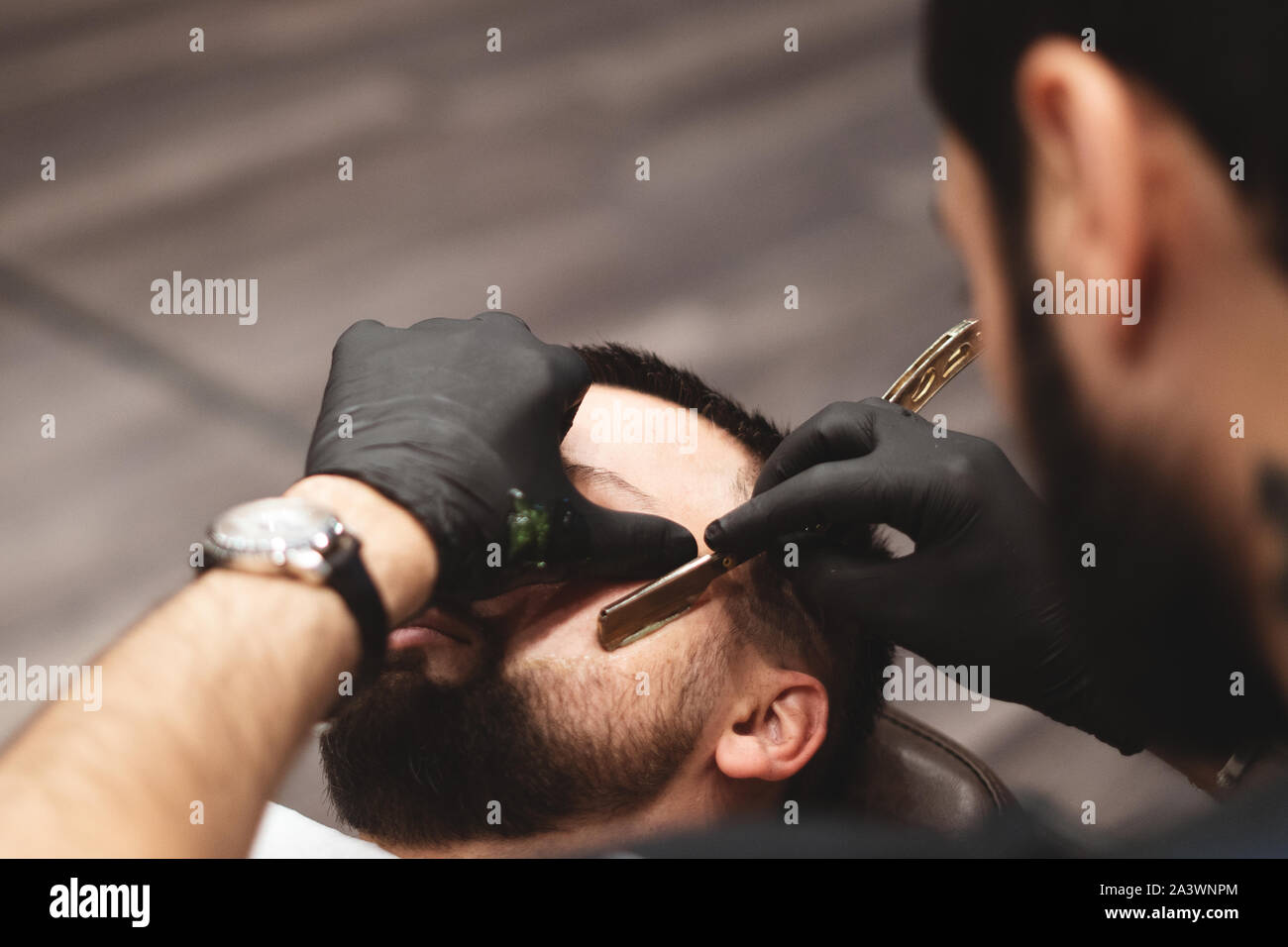 Rasieren ein Bart in einem Barbershop mit einer gefährlichen Rasiermesser. Friseur Bart kümmern ...