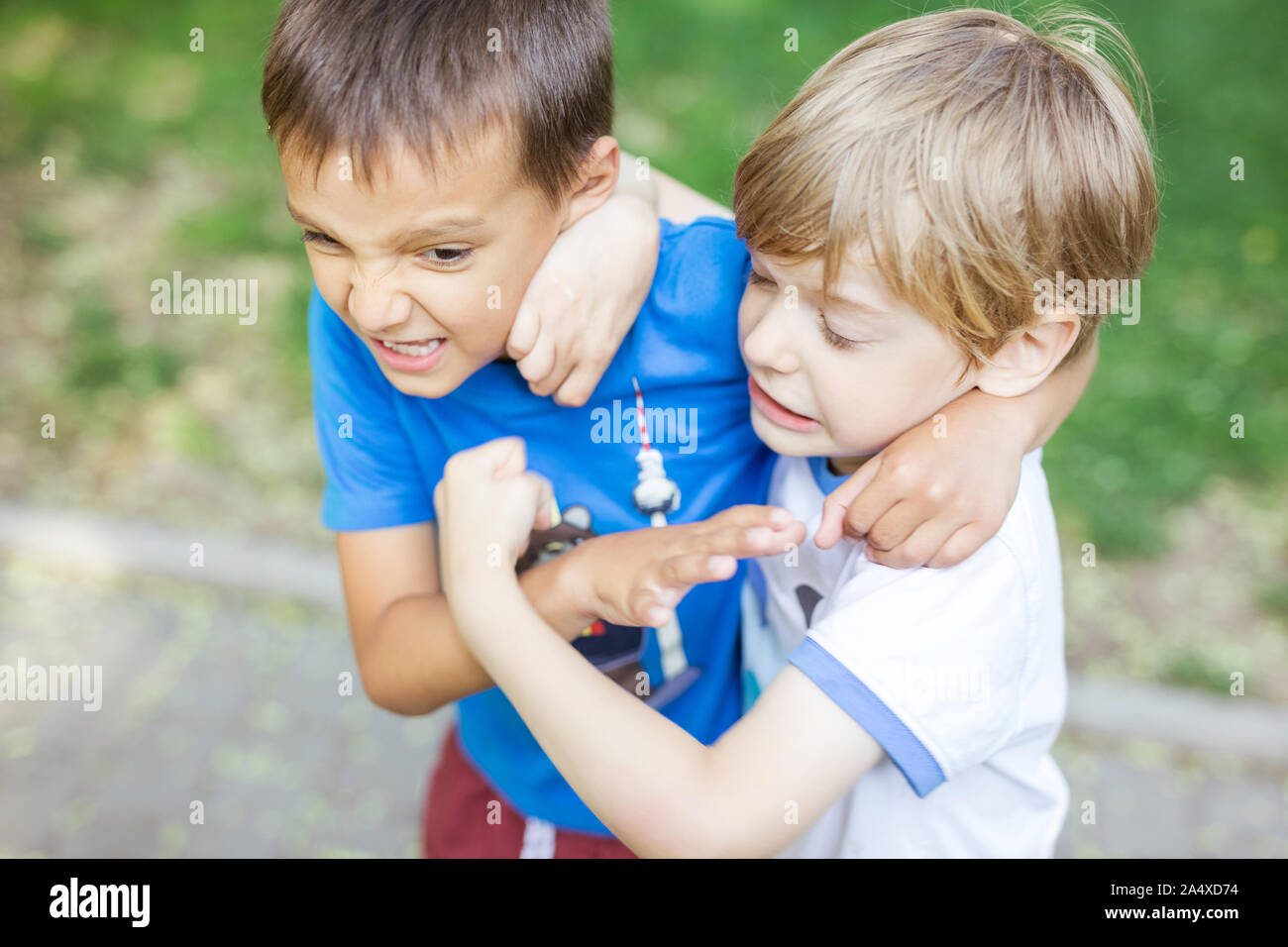 Zwei Jungen kämpfen im Freien. Freunde wrestling im Sommer Park. Geschwister Rivalität ...