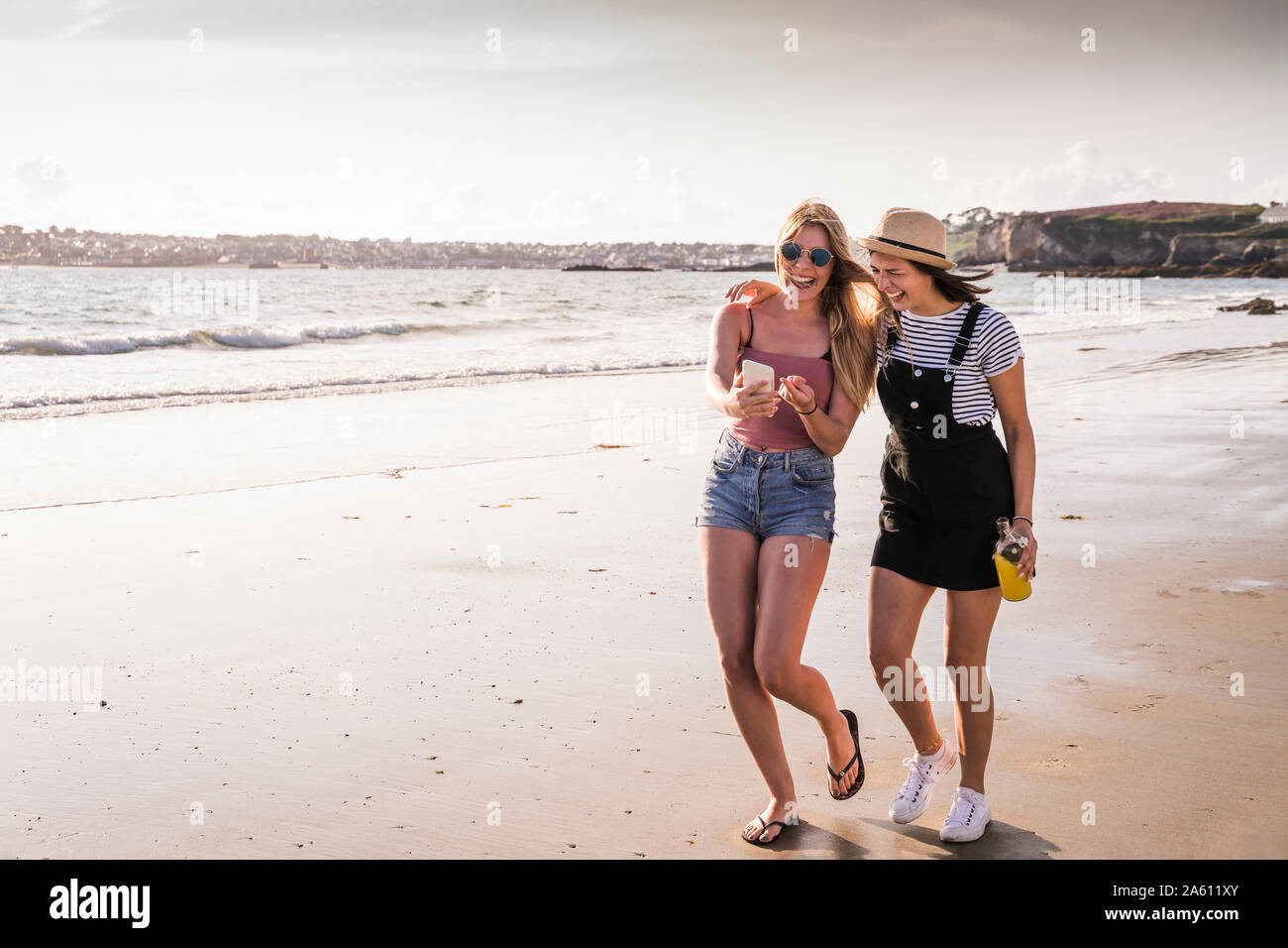 Zwei Freundinnen Spaß, Wandern am Strand, wobei Smartphone selfies ...