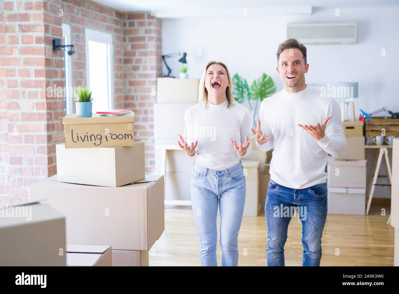 Junge schöne Paar stehen im neuen Zuhause um Kartons crazy und verrückt ...