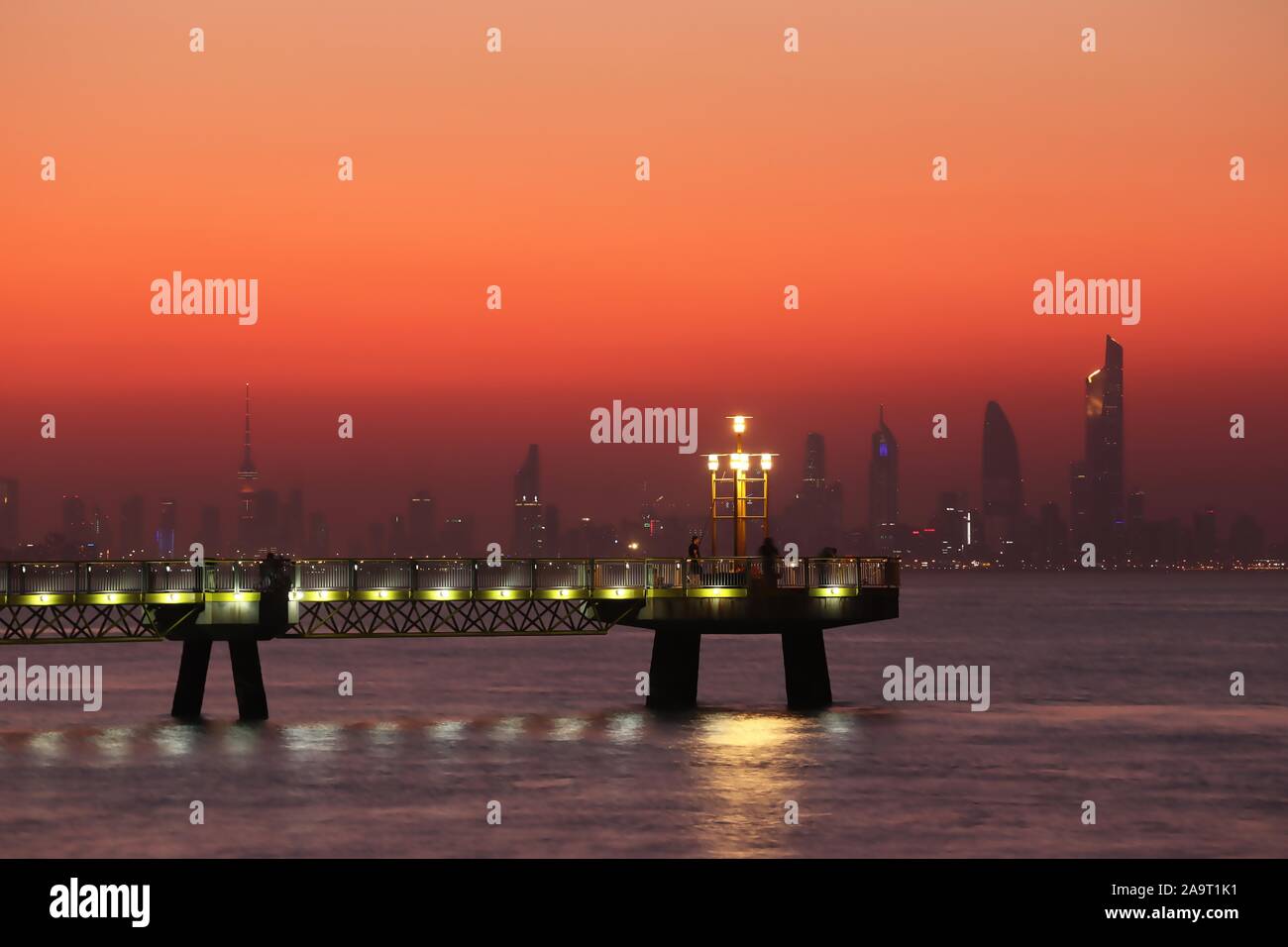 Pier bei sonnenuntergang mit skyline silhouette von kuwait stadt herein ...