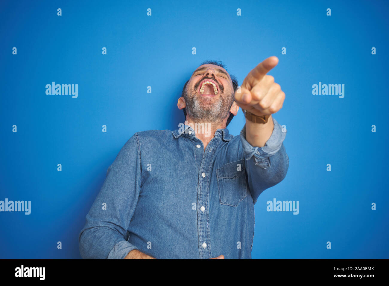Stattliche mittleren Alters älterer Mann mit dem grauen Haar über isolierte blauen Hintergrund ...