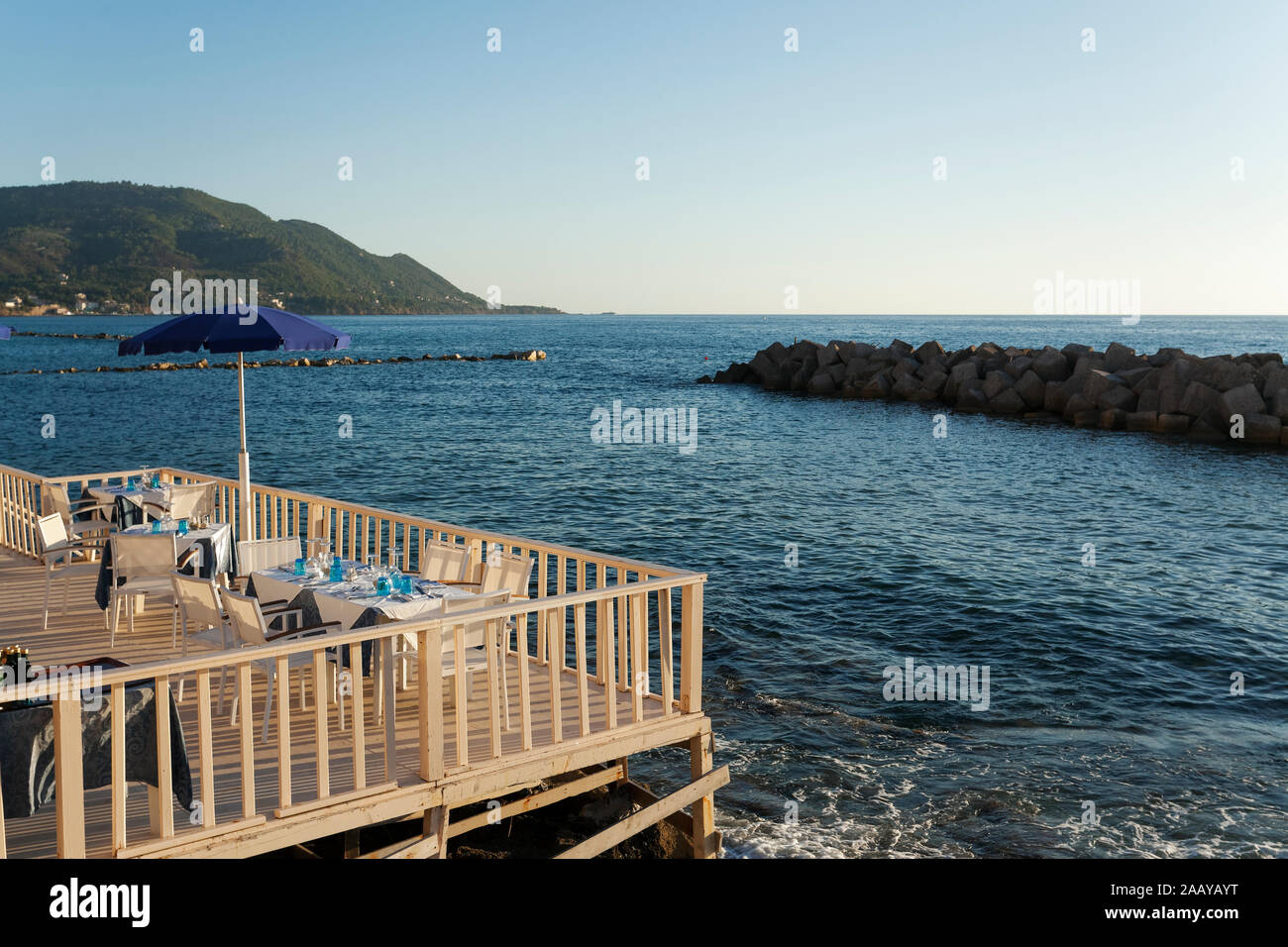 Terrasse am Meer mit Tisch, Sonnenschirm und Dinind Tabellen, Strand ...