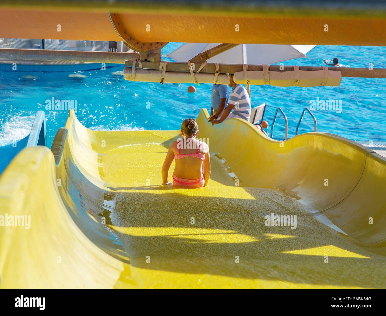 Rückansicht eines Mädchens rutschen Wasserrutsche in ein Schwimmbad an ...