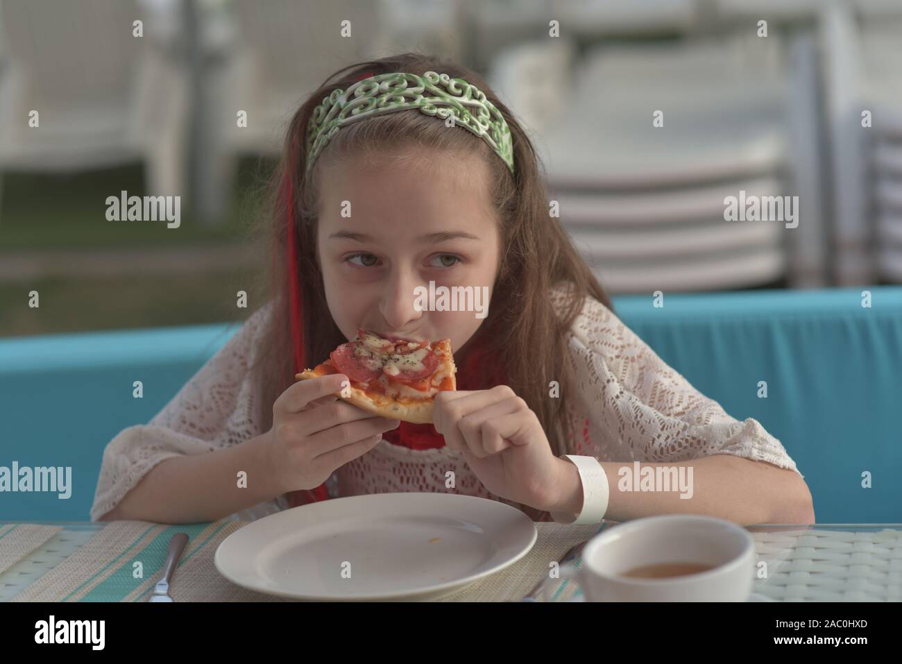 Porträt der jungen Frau mit Pizza im Cafe. Mädchen 9 Jahre alt isst Pizza im Sommer Cafe auf ...
