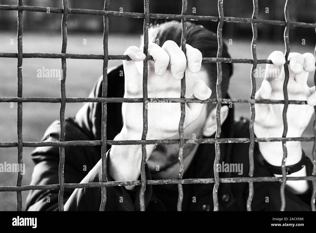 Die Hände des Gefangenen auf einem stahlgitter Nahaufnahme der Gefangene, hinter Gittern, hält ...