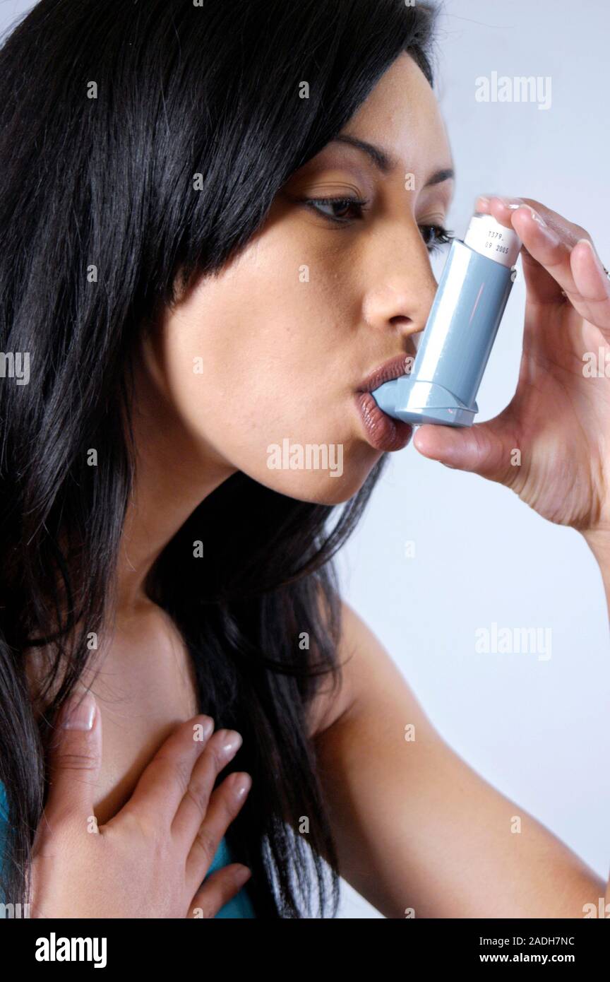 MODEL RELEASED. Asthmaanfall. Junge Frau mit einem Inhalator bei einem ...