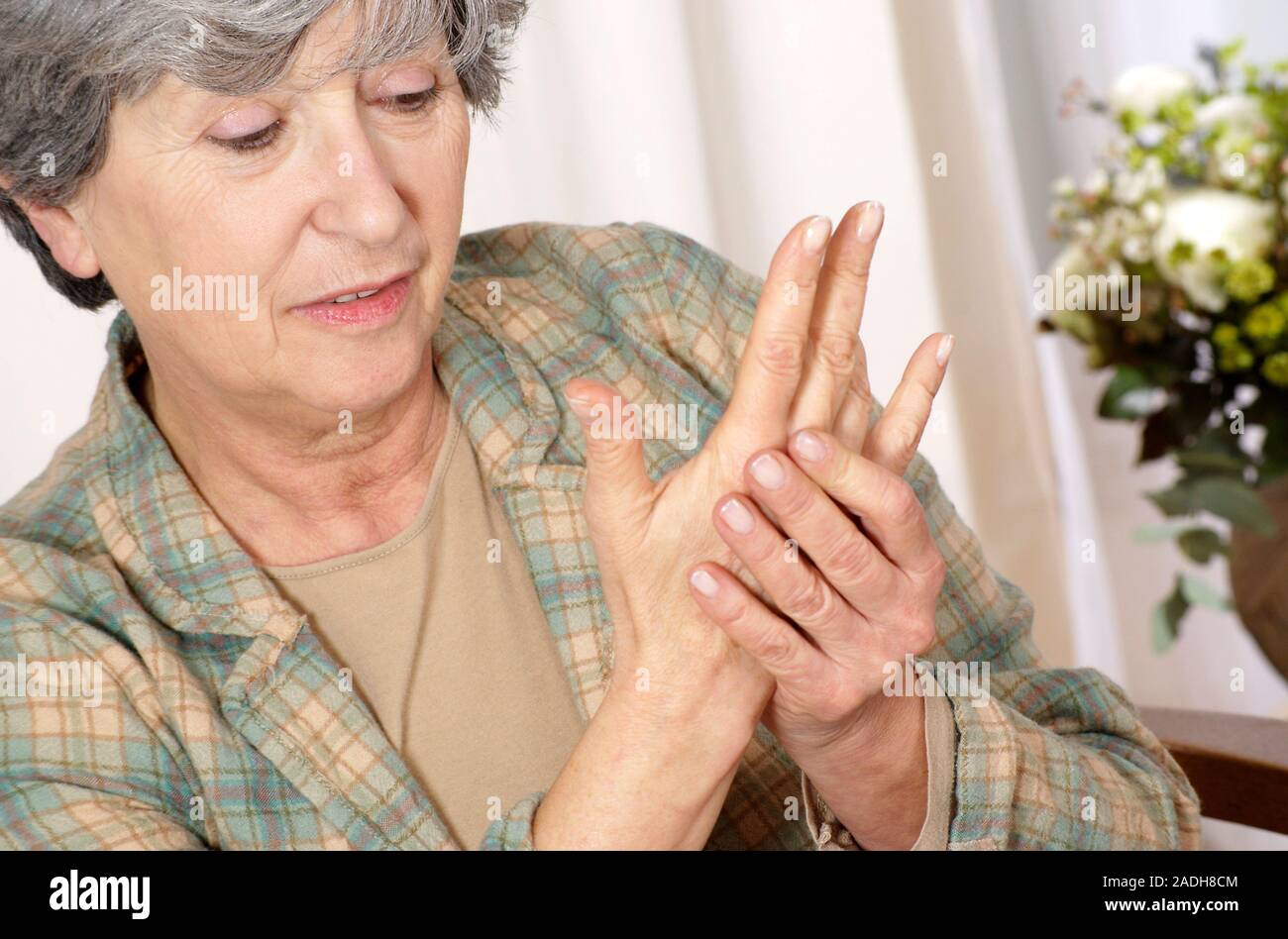 MODEL RELEASED. Frau mit Osteoarthritis ihre wunde Hand reiben. Dies ...