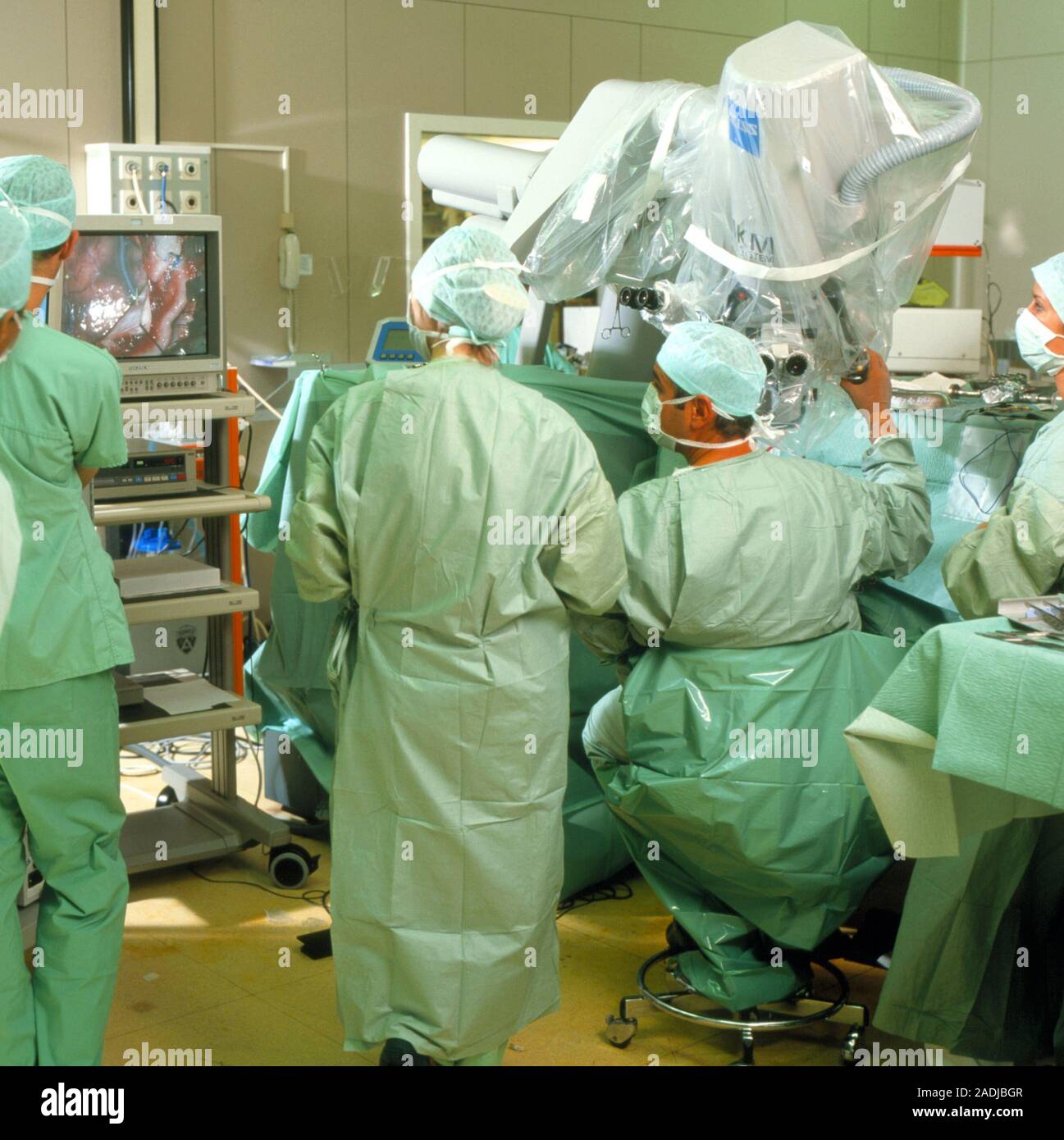 Gehirnchirurgie. Neurochirurg (sitzend) führt die Mikrochirurgie auf das Gehirn eines Patienten ...