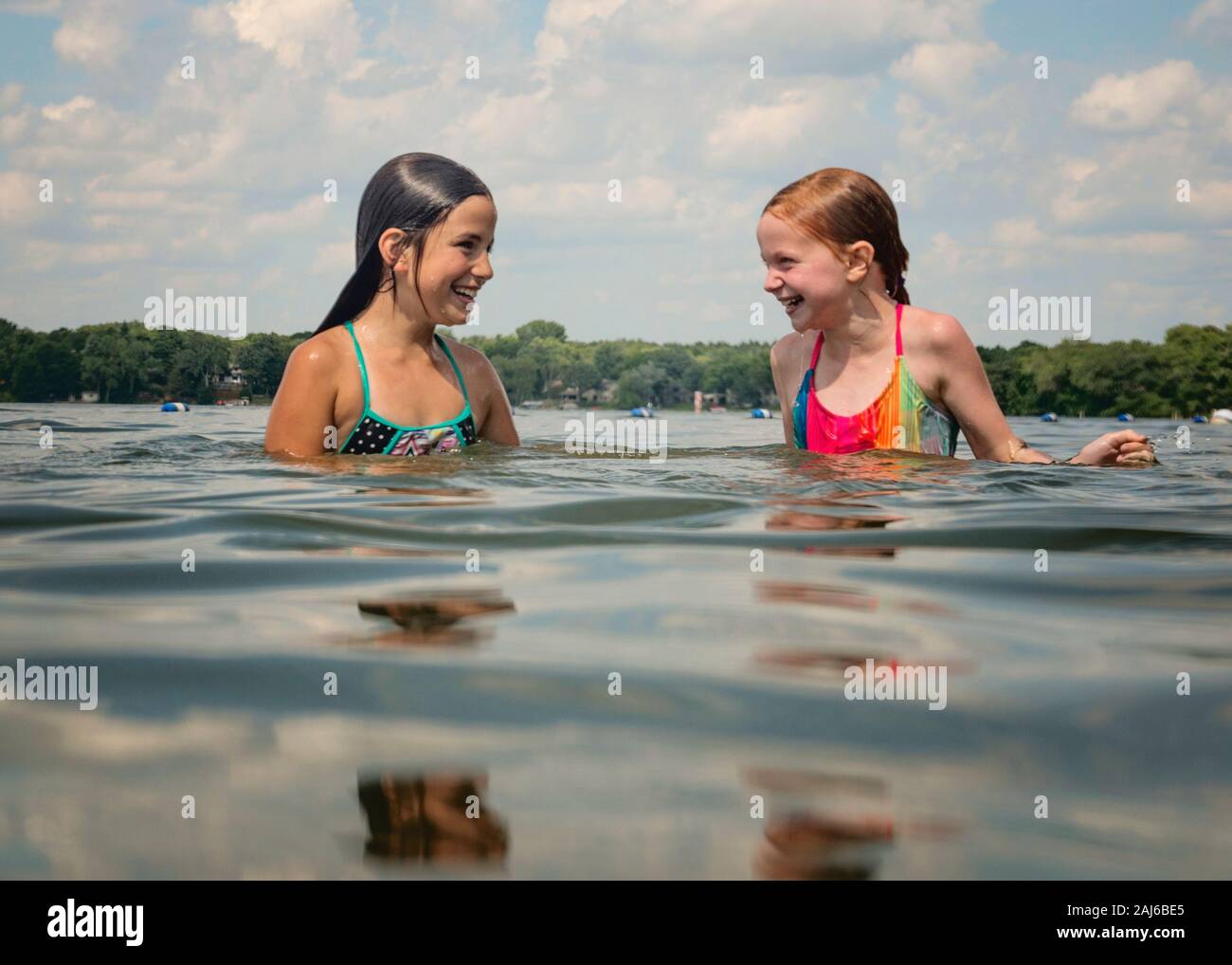 Zwei junge Mädchen in Badeanzügen spielen im Wasser in einem See ... Zwei junge Mädchen in Badeanzügen spielen im Wasser in einem See ...