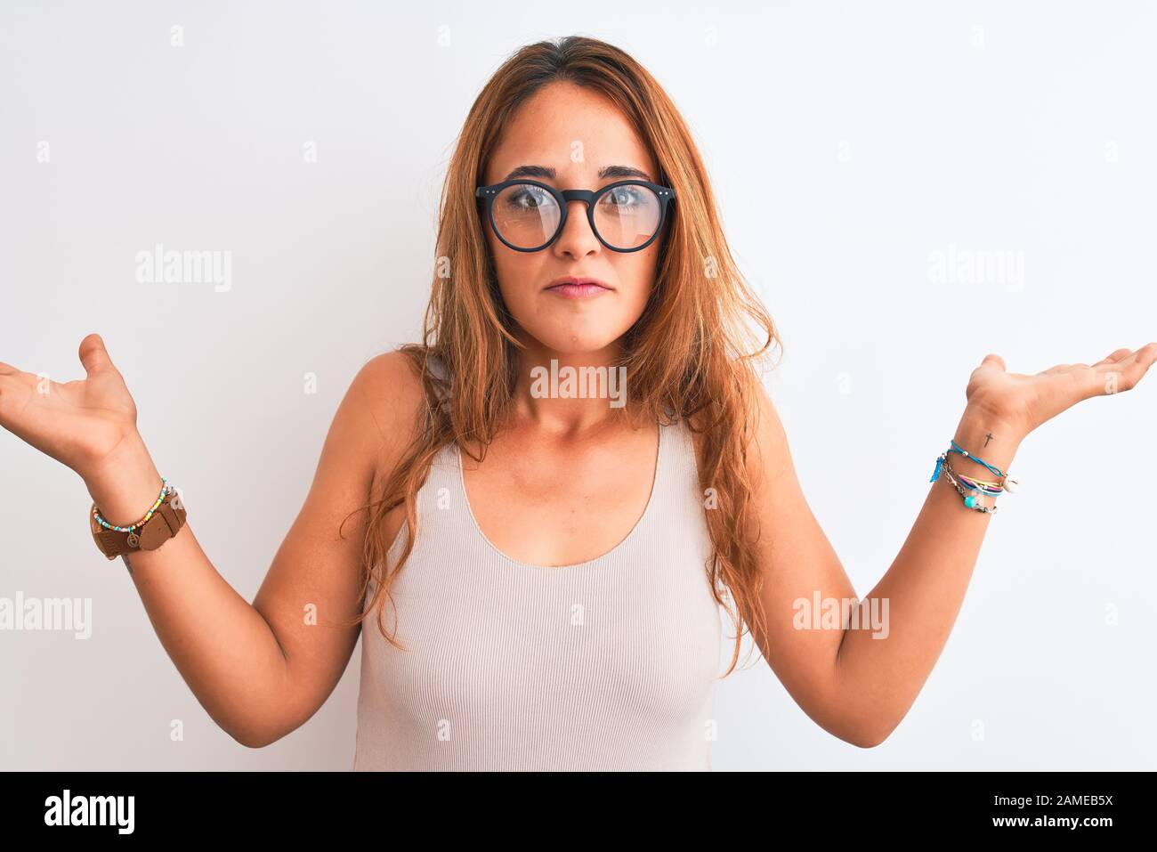 Junge Rotkopffrau, die eine Brille trägt, die über weißem isoliertem ... Junge Rotkopffrau, die eine Brille trägt, die über weißem isoliertem ...