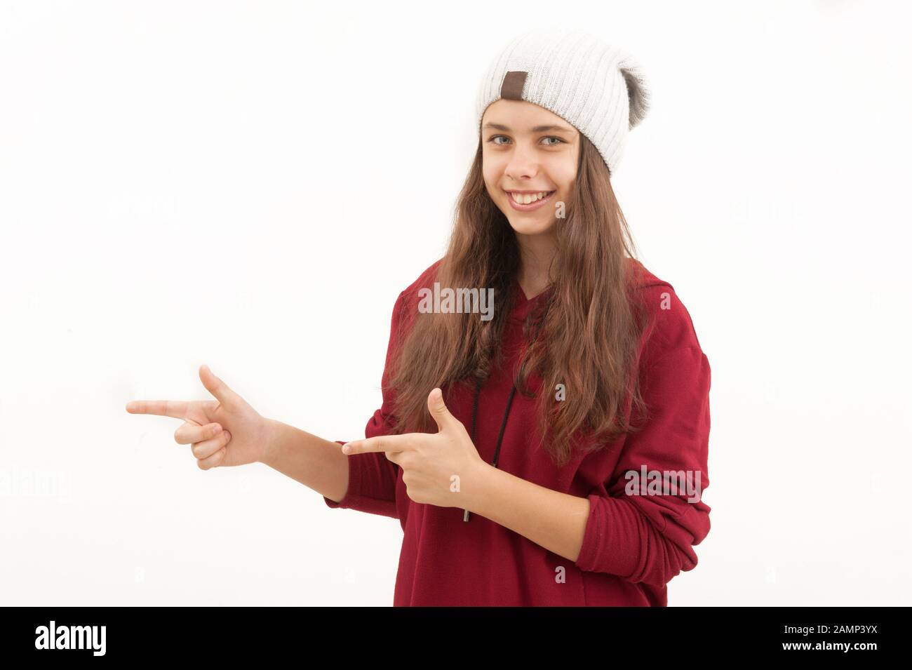 Das Mädchen in einem Hut zeigt die Finger auf einen weißen Hintergrund ...