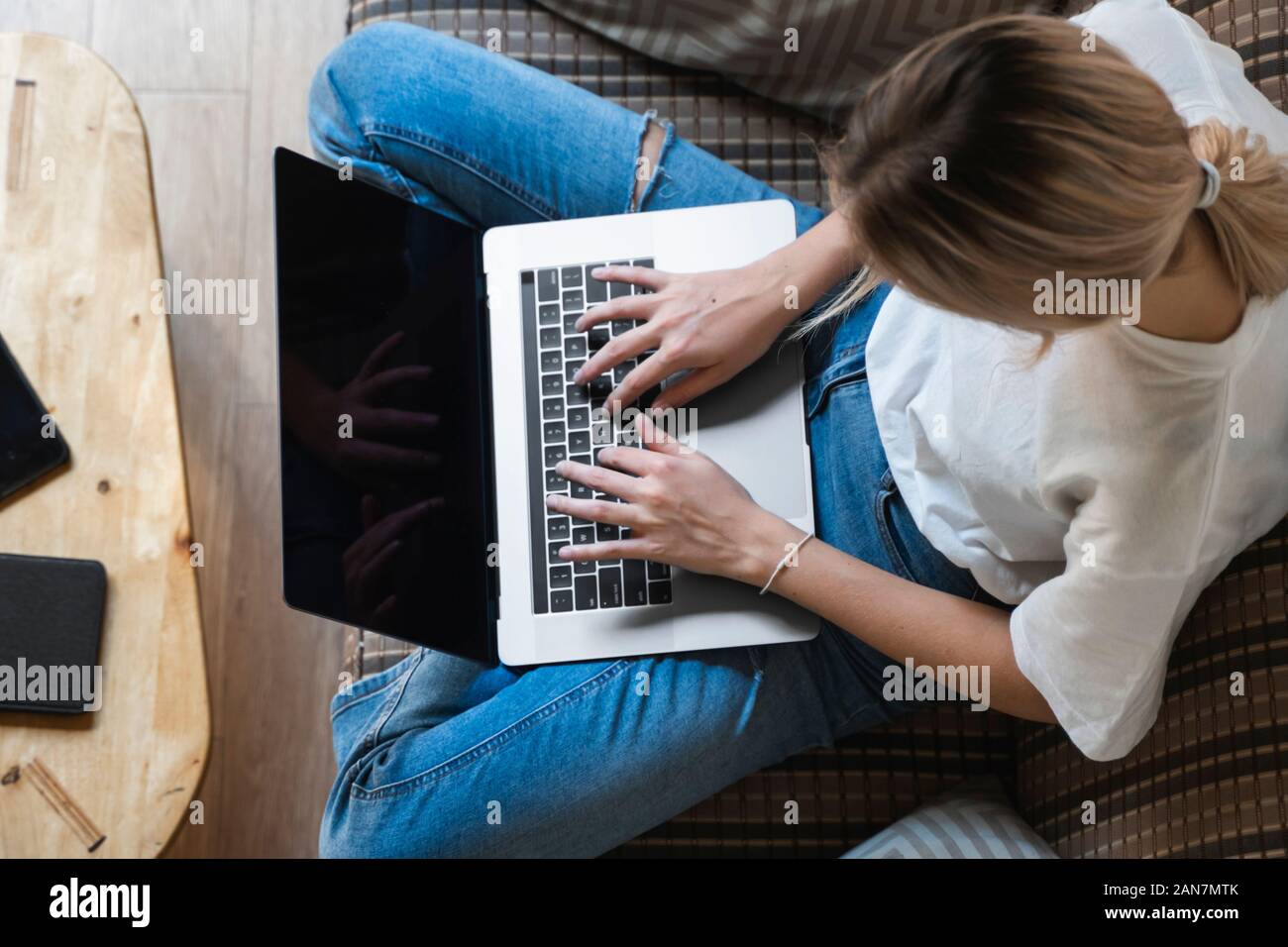 Frau mit einem Notebook sitzt auf einem Sofa. Studieren und Arbeiten ...
