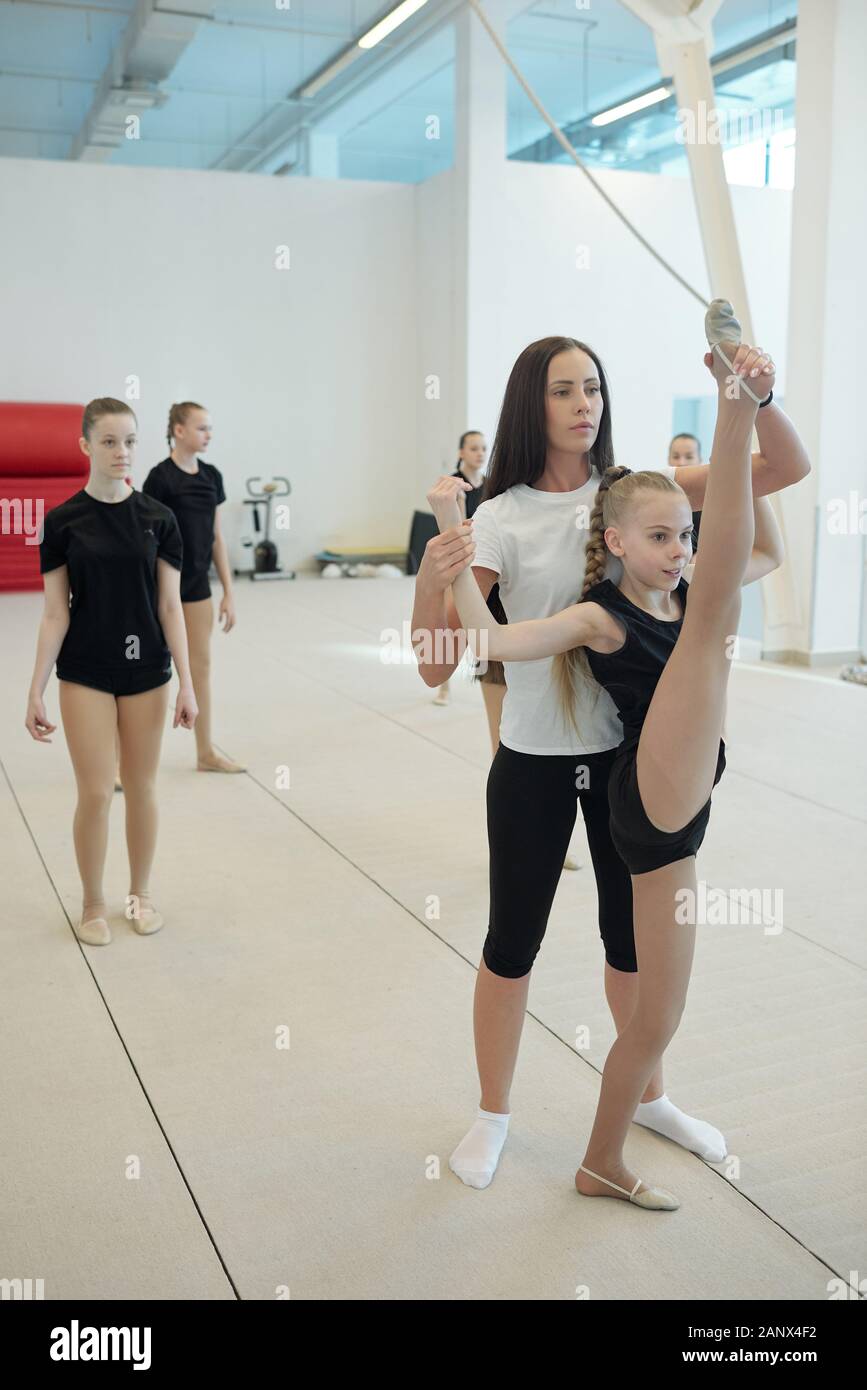 Cheerleading Lehrer unterstützen Mädchen tun, vertikal stehend Split ...