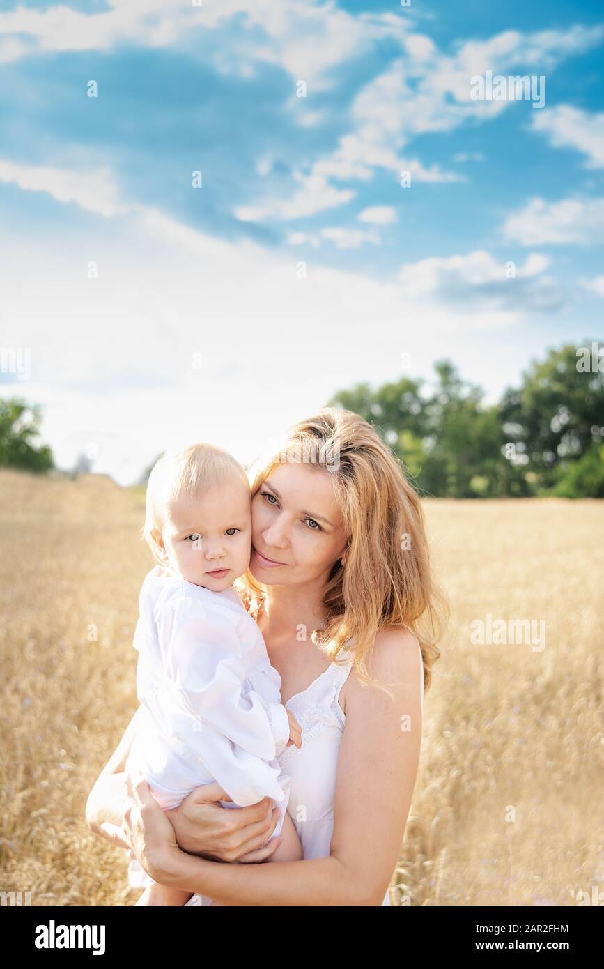Schöne Mutter und kleine Tochter auf dem Weizenfeld am sonnigen Tag ...