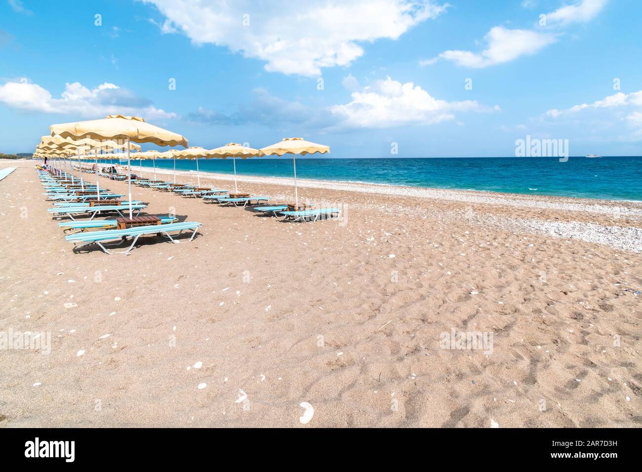 Leere Sonnenliegen und Sonnenschirm am Strand von Afandou in der Nähe ...
