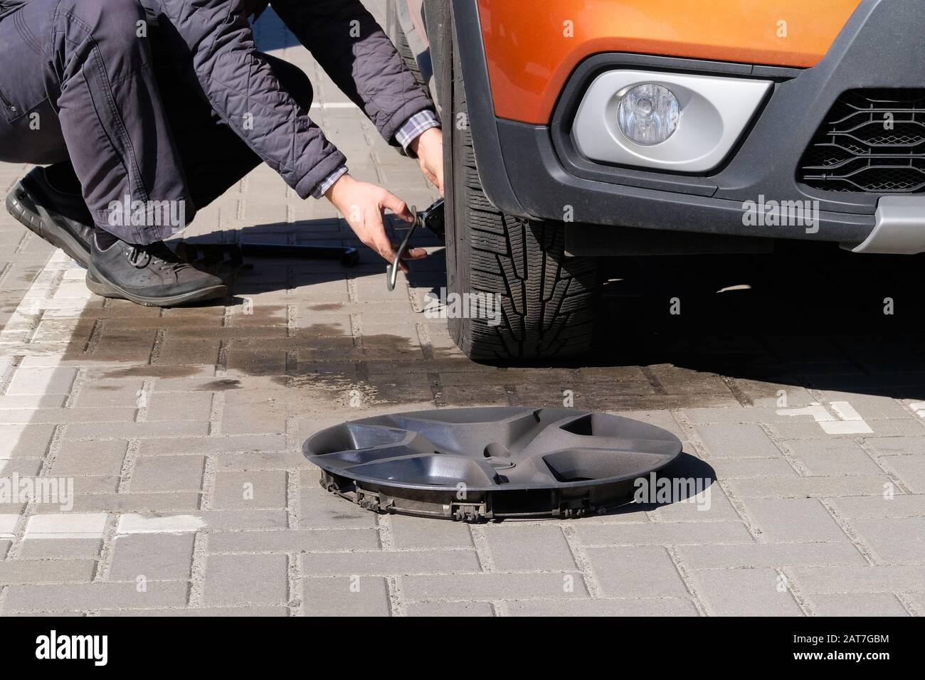 Der Mann wechselt das Rad nach einer Pkw-Pause. Beschädigter Autoreifen ...