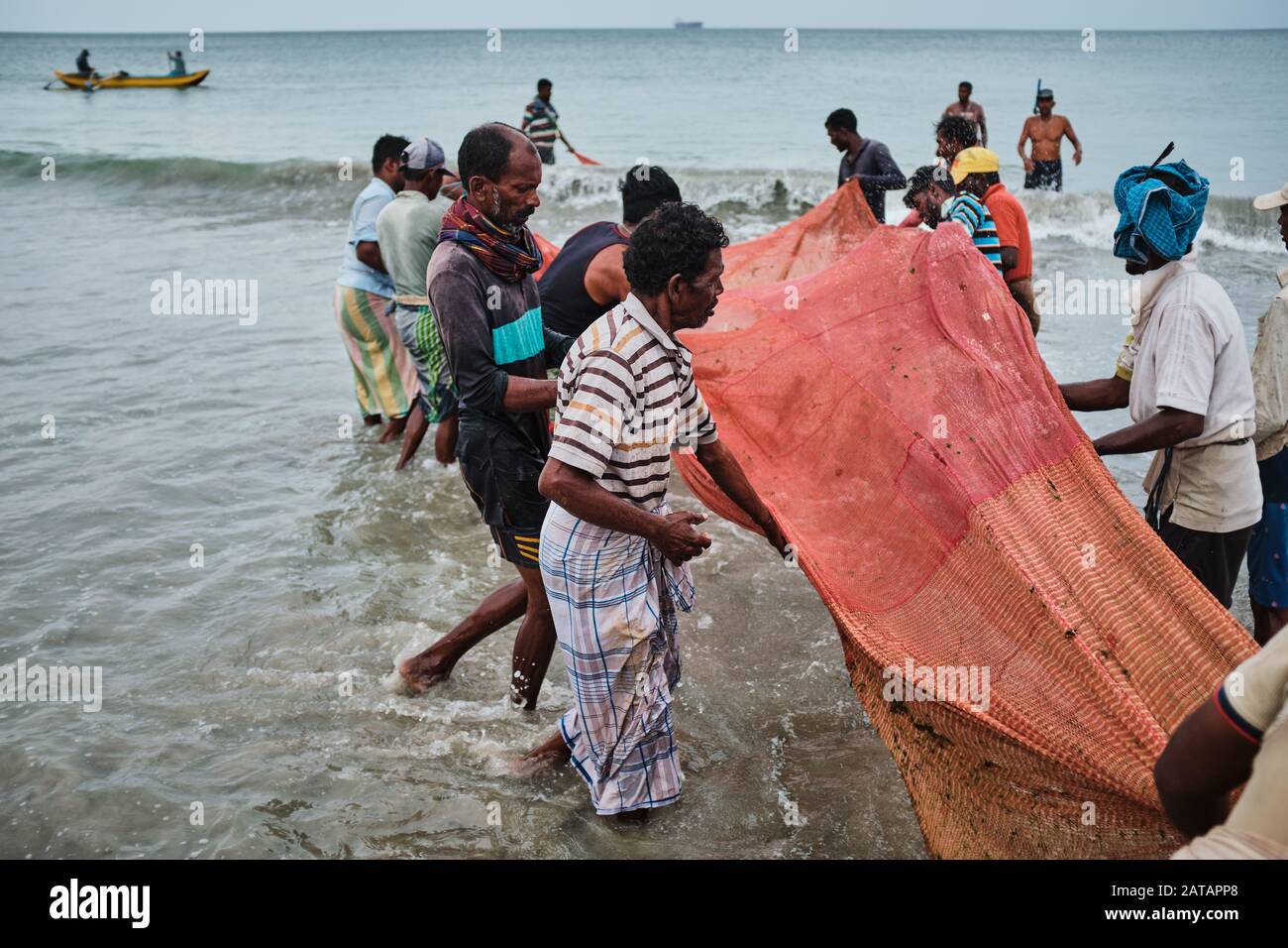 Fischer ziehen die Netze am Strand in Sri Lanka aus dem Meer. Die Stadt ...