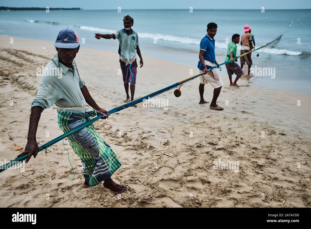Fischer ziehen die Netze am Strand in Sri Lanka aus dem Meer. Die Stadt ...