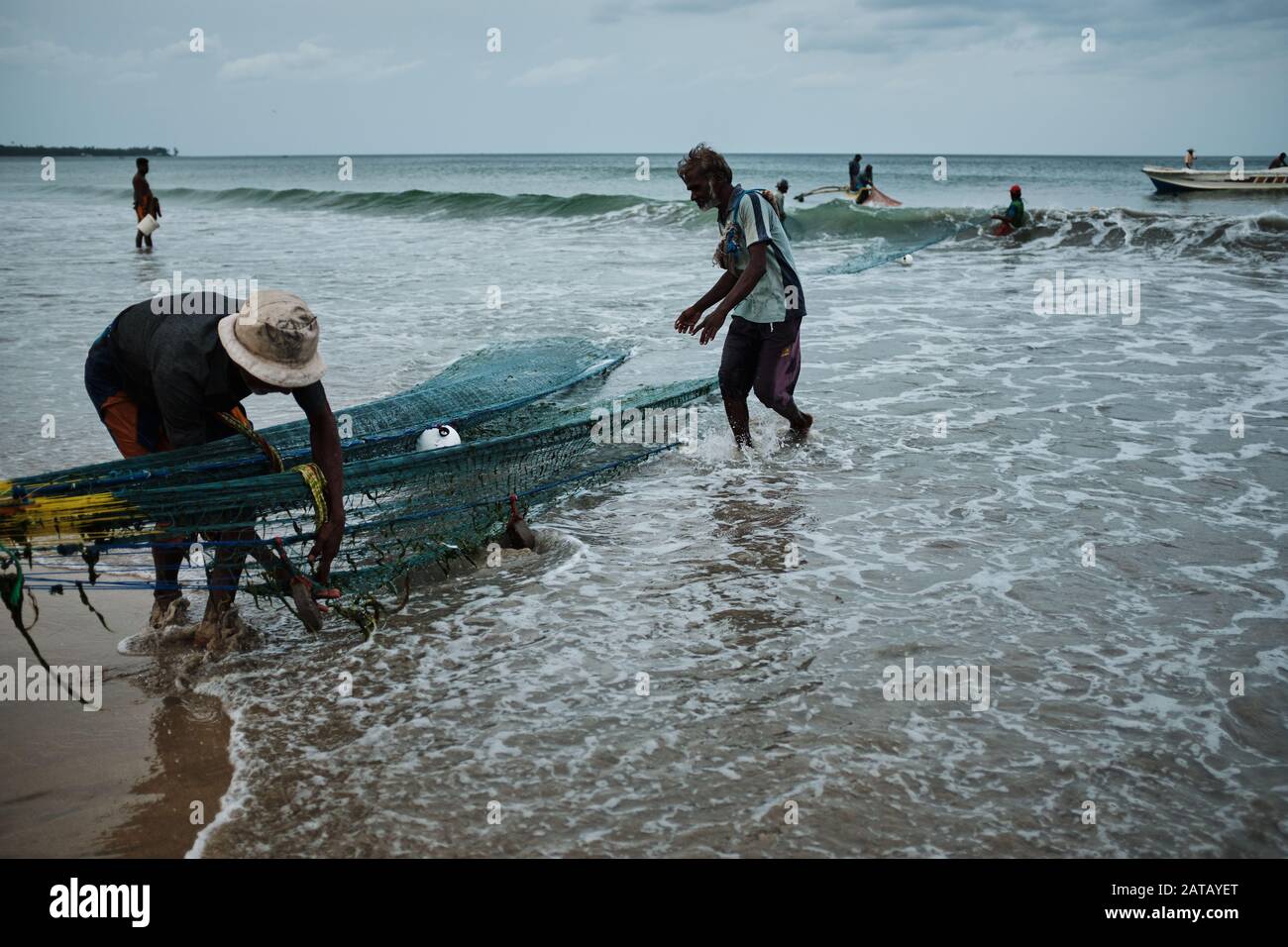 Fischer ziehen die Netze am Strand in Sri Lanka aus dem Meer. Die Stadt ...