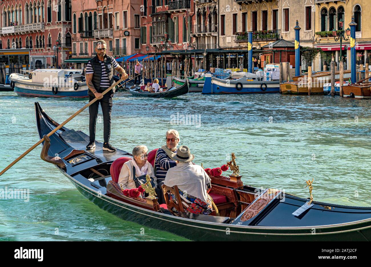 Ein Gondelfahrer lenkt seine Gondel mit drei Touristen, die eine ...
