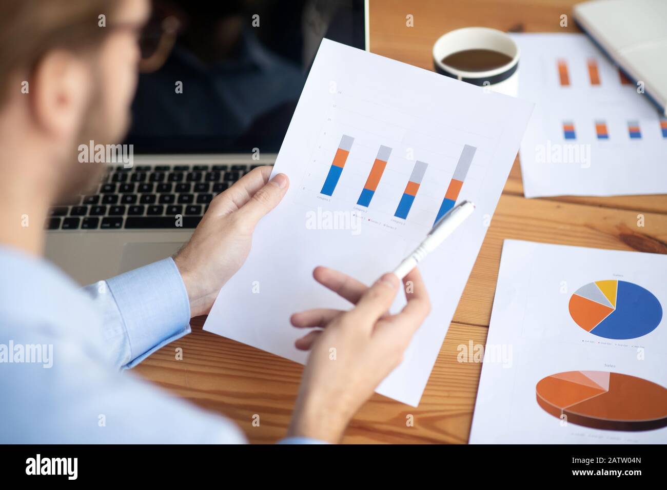 Diagrammanalyse. Junger Geschäftsmann in Brille, der an einem Tisch ...