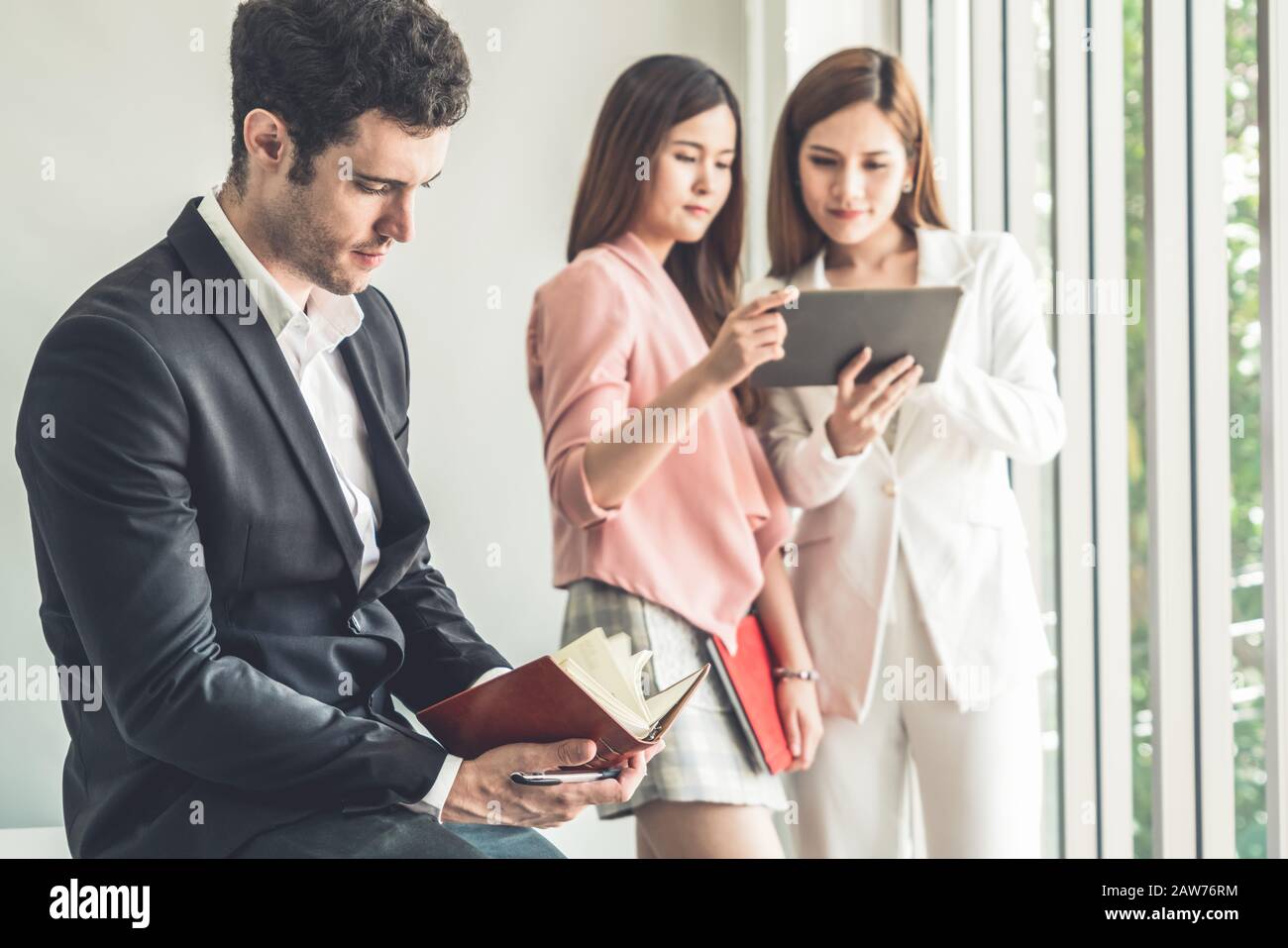 Glückliche junge gut aussehender Geschäftsmann lesen Buch und Arbeiten im Büro mit Kollegen und ...