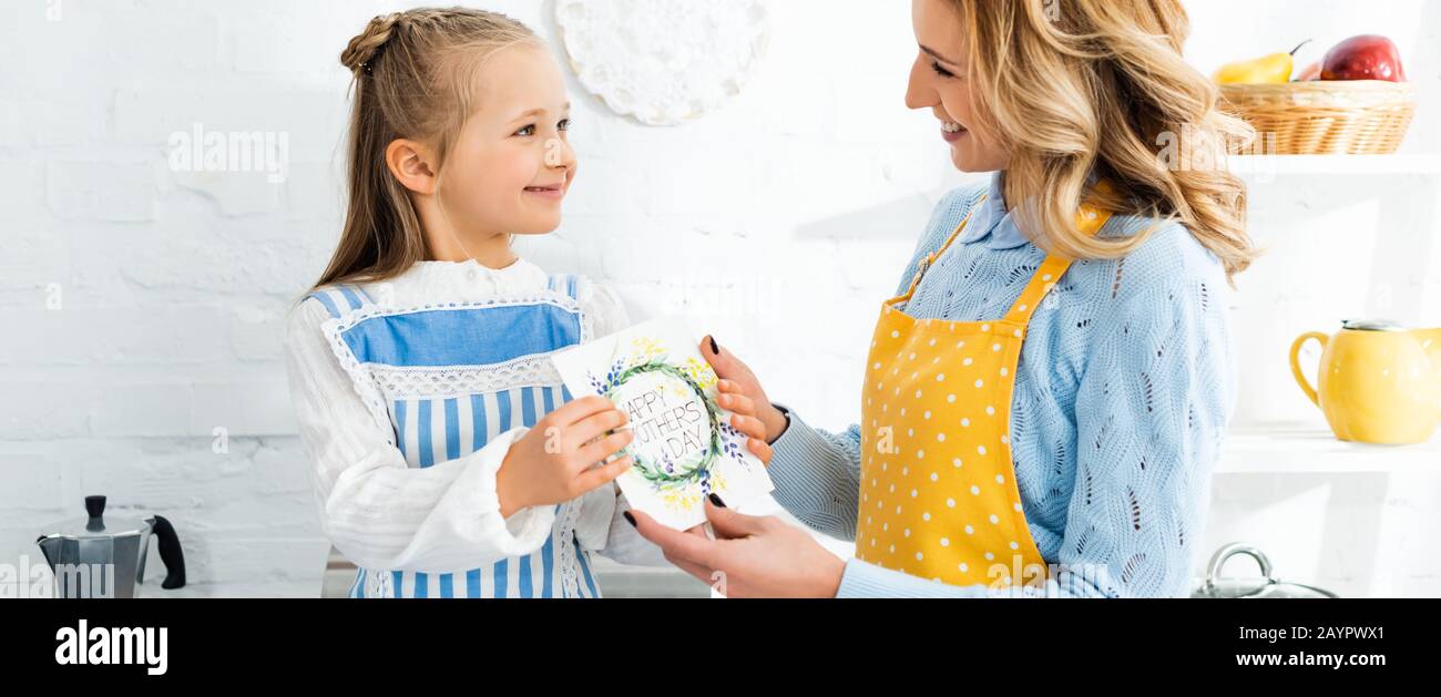 Panoramaaufnahme der Tochter, die der lächelnden Mutter eine Karte mit ...