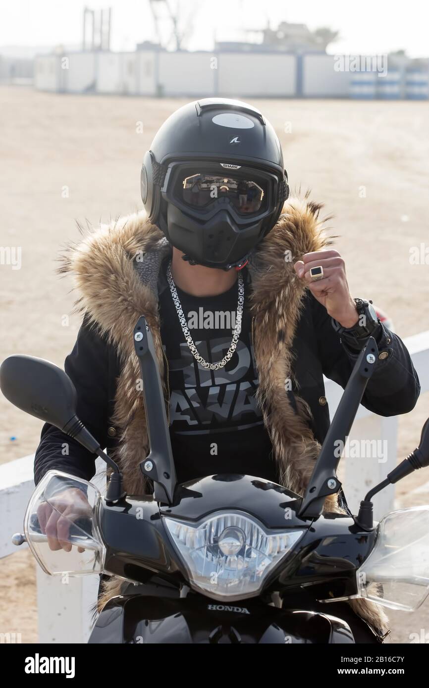 Marokkanischer junger Mann, der eine Bluse mit Pelz und Helm trägt ...