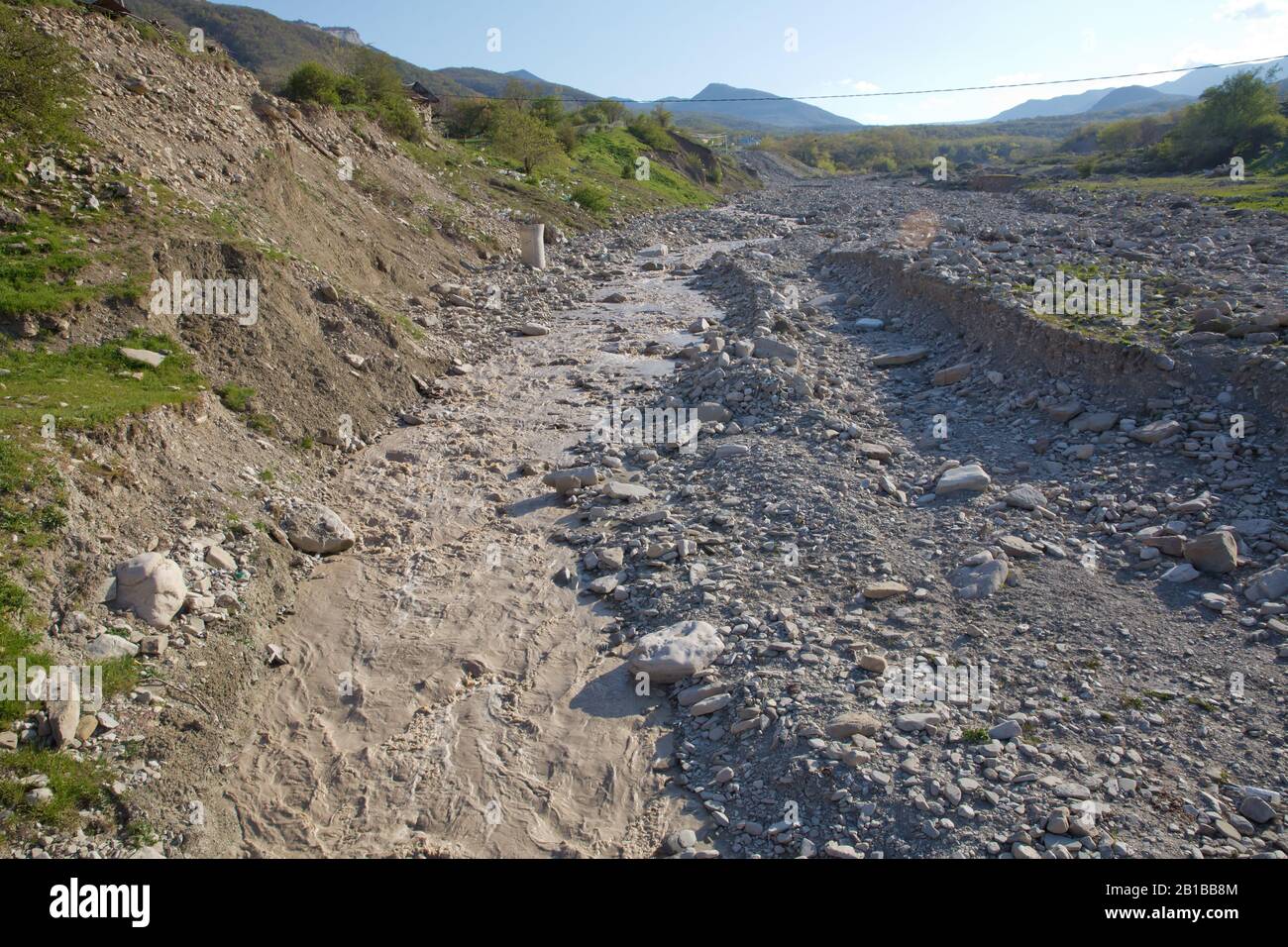 Steiniger Fluss, hohe grüne Berge im Hintergrund. Felsen auf Flussbett ...