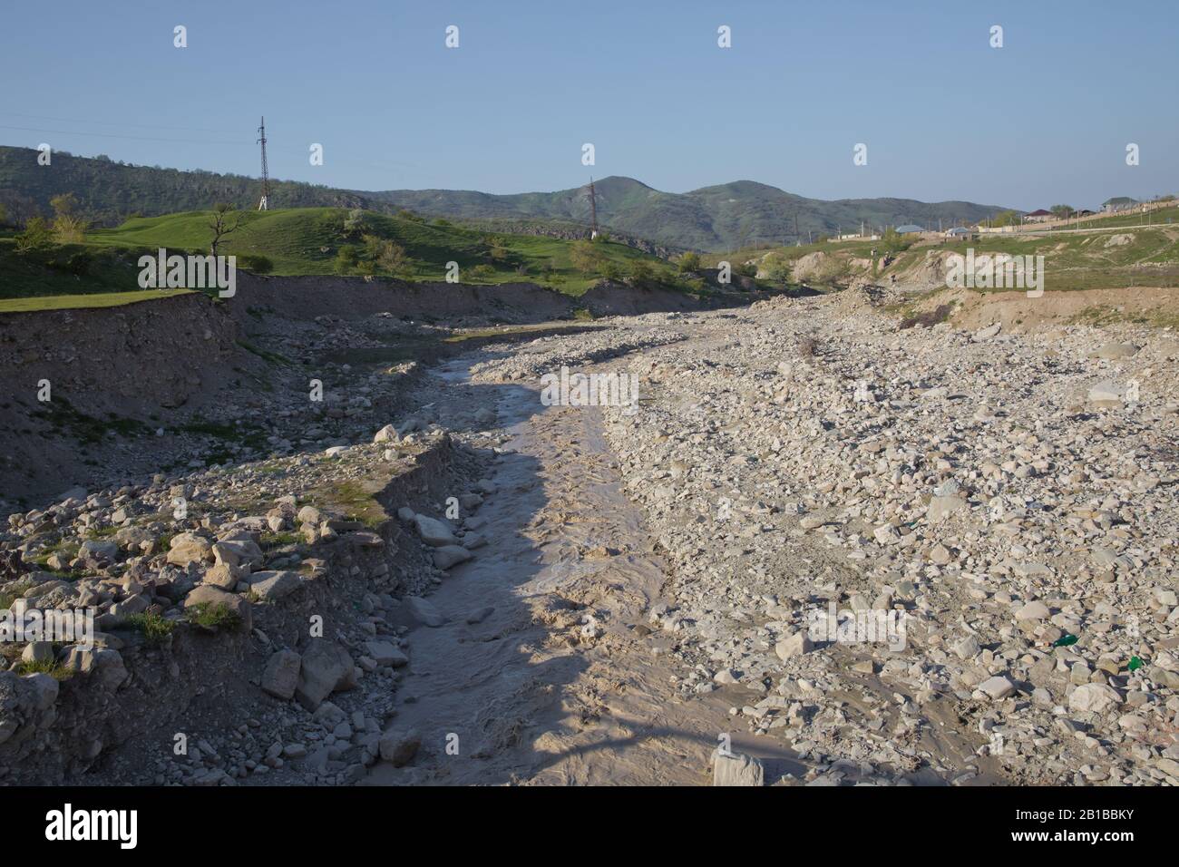 Steiniger Fluss, hohe grüne Berge im Hintergrund. Felsen auf Flussbett ...