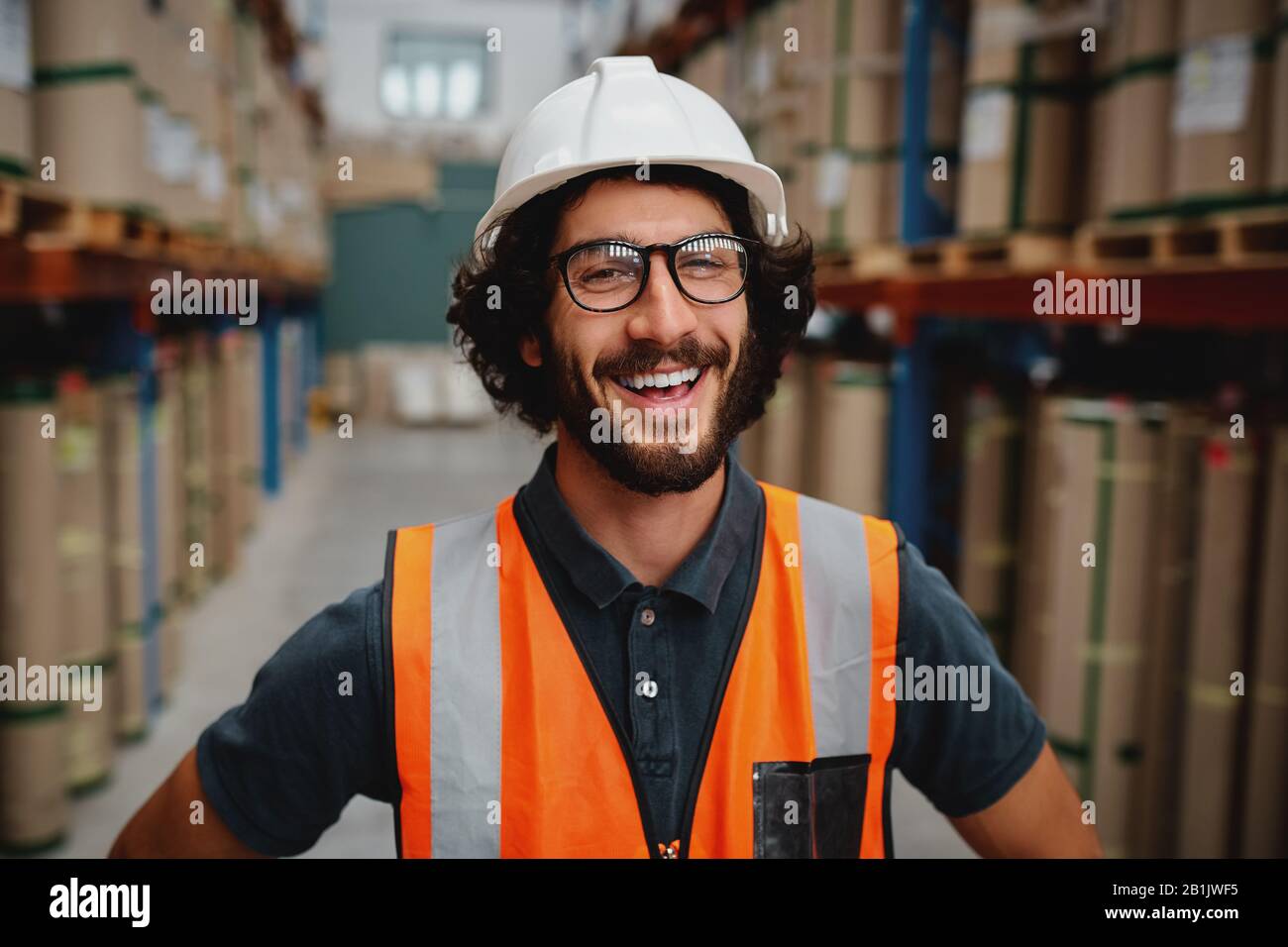 Fröhlicher männlicher Vorgesetzter im Lager mit weißem Helm und ...