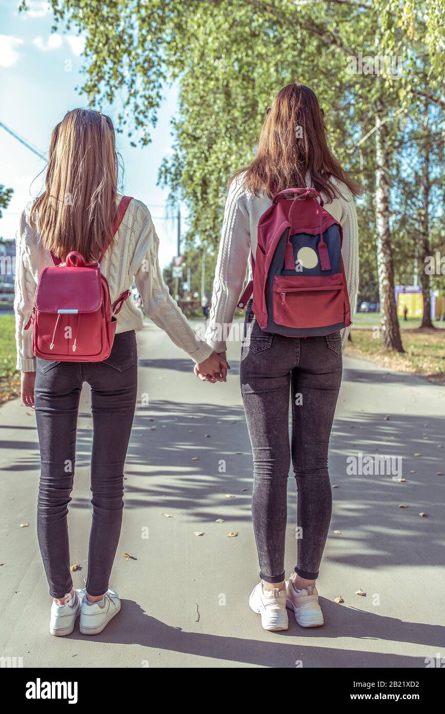 Zwei Mädchen Schulmädchen halten sich gegenseitig in die Hand und kehren nach der Schule und dem ...