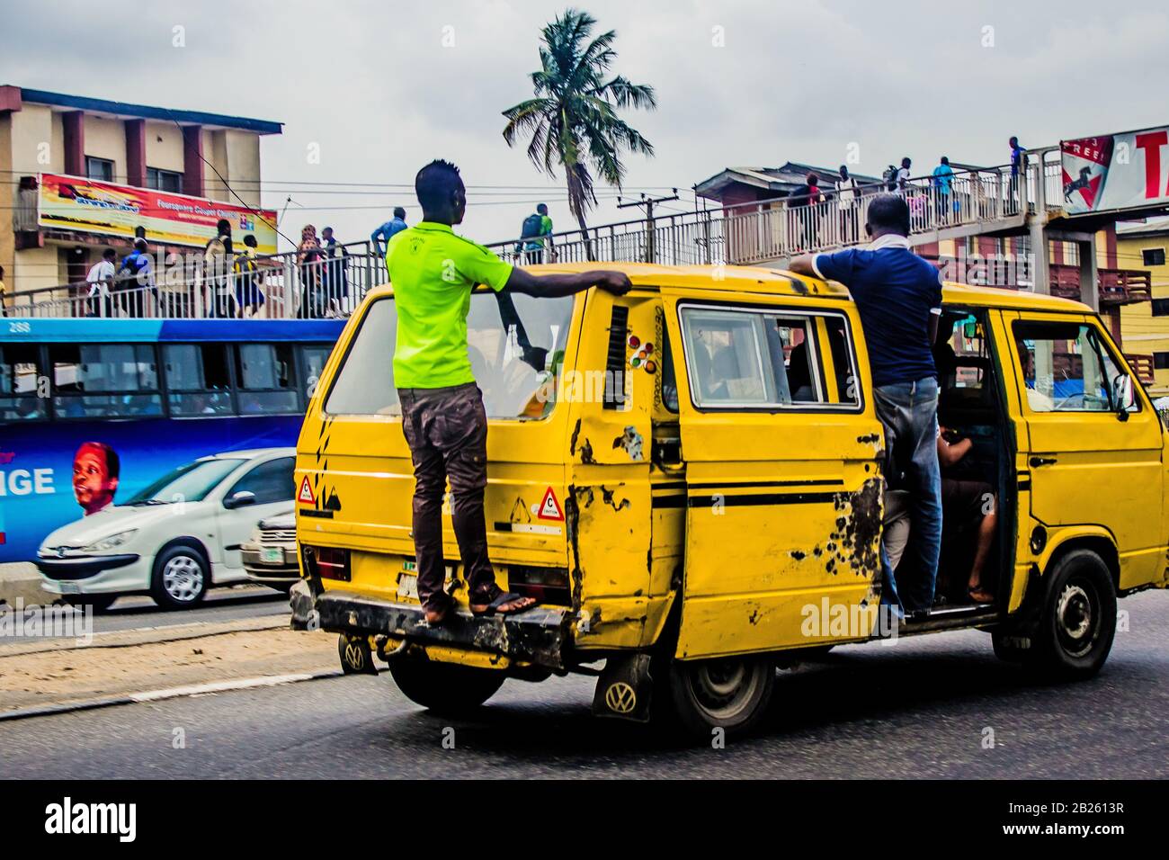Die Menschen hängen mit einem Bus (danfo) auf einer Straße in Lagos ...