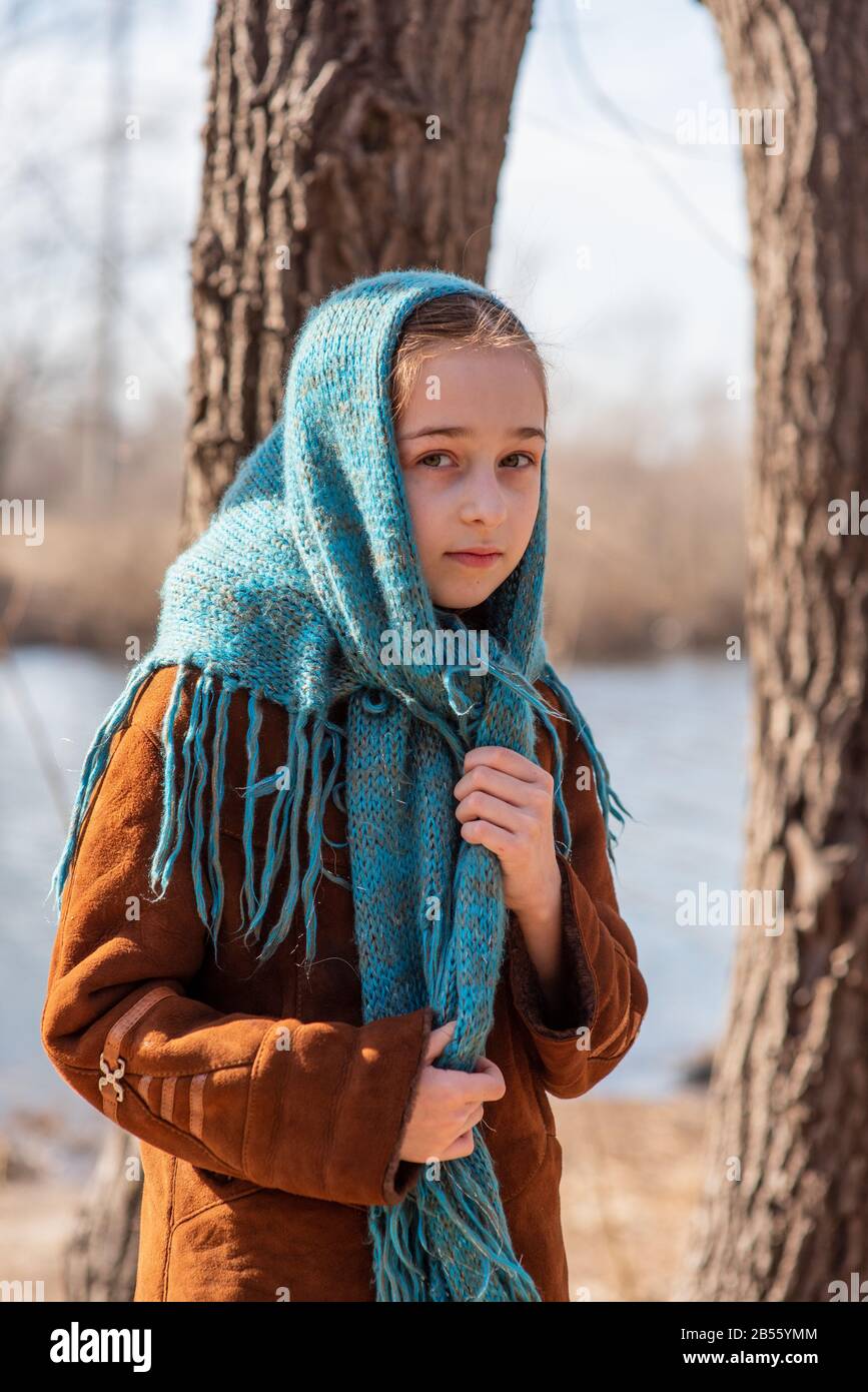 An einem sonnigen Tag steht ein Mädchen in einem hellen Schaffellmantel ...