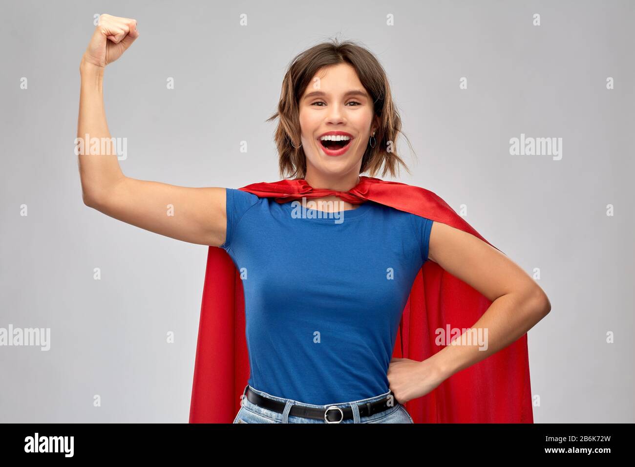 Frauen- und Personen-Konzept - fröhliche Frau im roten superhelden-kap ...