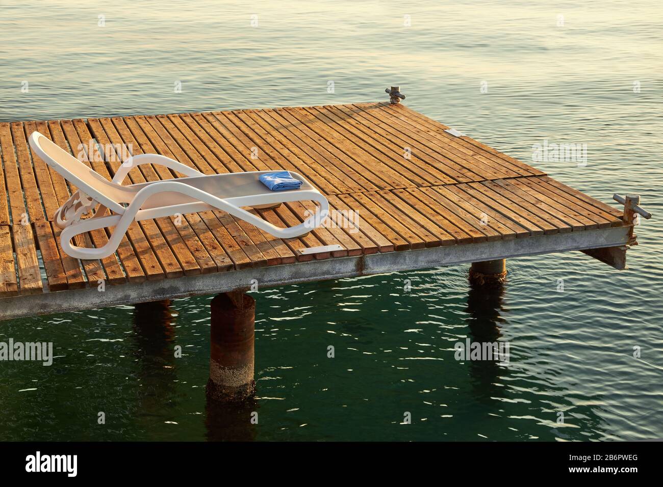 Strandliege mit einem darauf liegenden Handtuch befindet sich an einem ...