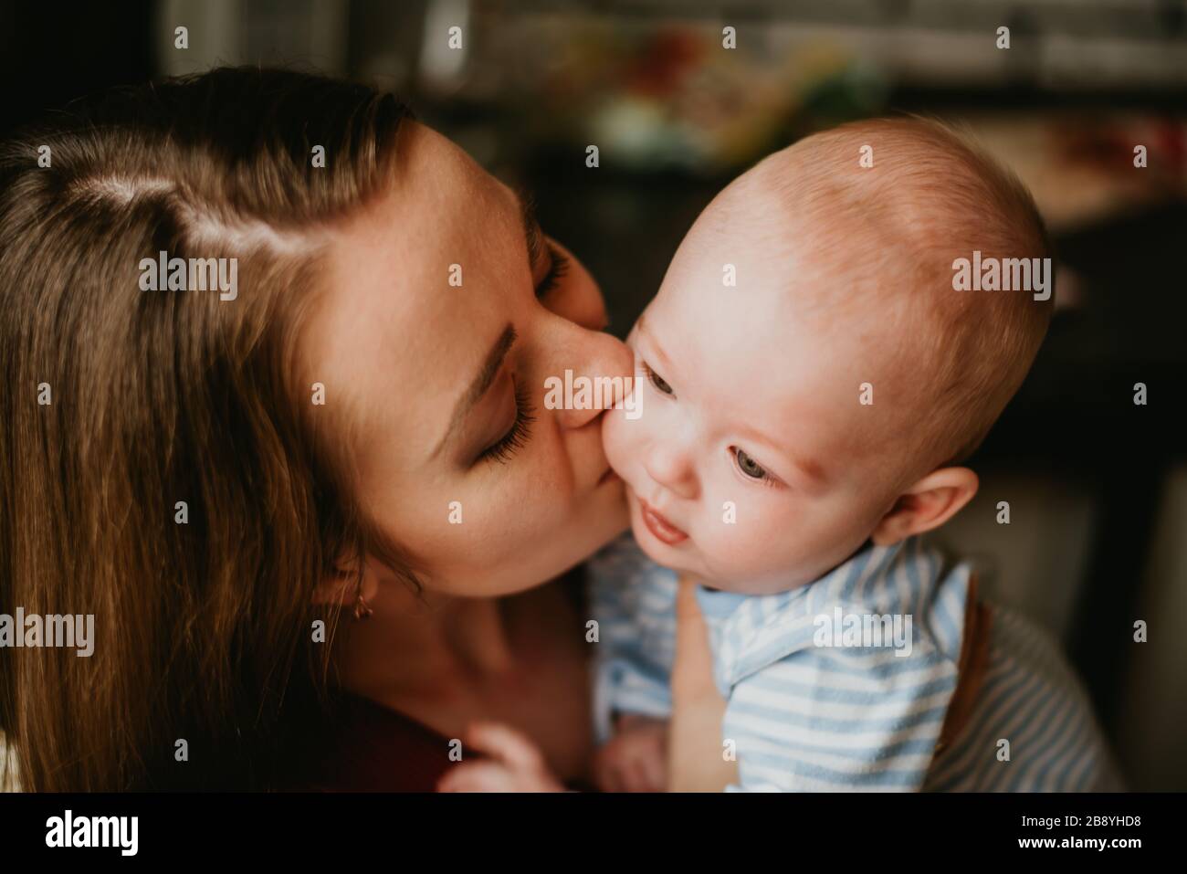Eine Mutter hält ein Kind in den Armen. Eine Mutter küsst ein Kleinkind ...