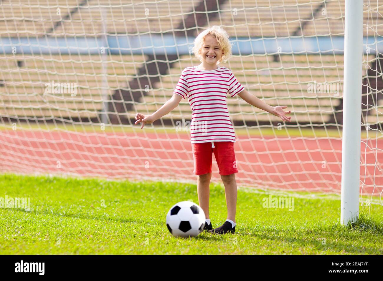 Kinder spielen auf dem Stadionfeld im Freien Fußball. Kinder erzielen ...